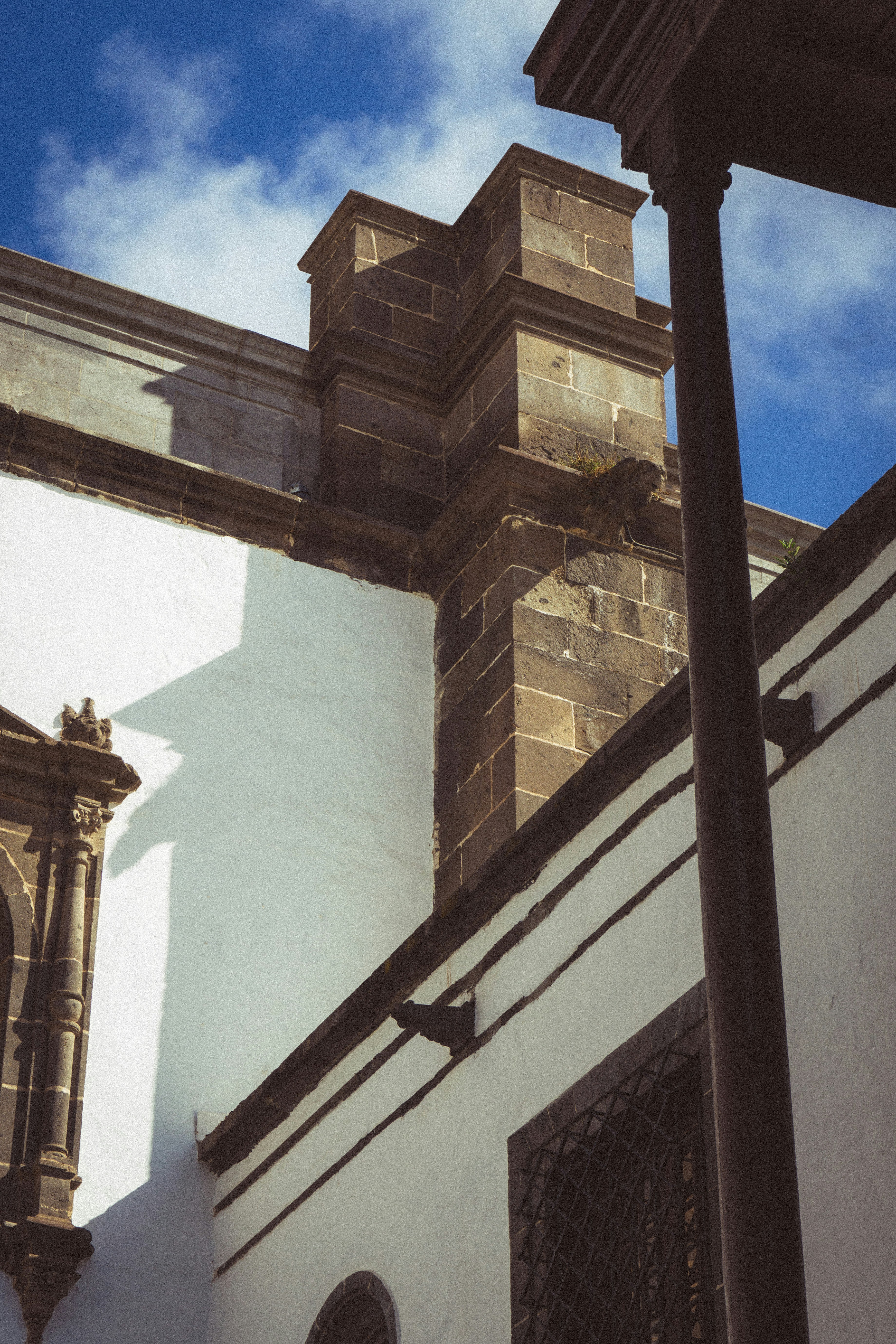 Cornerstone in Sunlight: Charcoal Stone Meets White Walls Under a Cerulean Sky