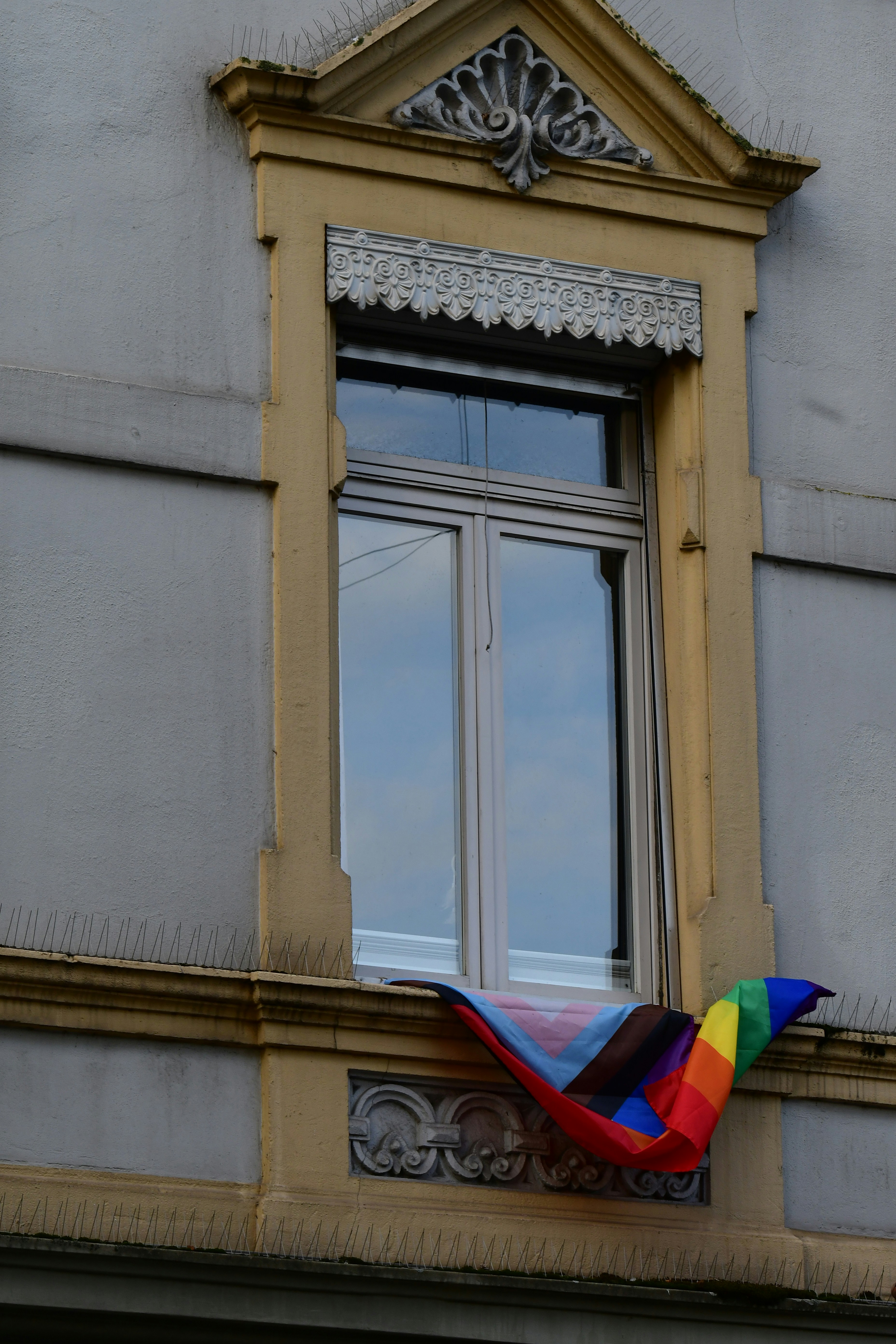 Rainbow Banner on a Classic Window: A Quiet Facade's Colorful Accent