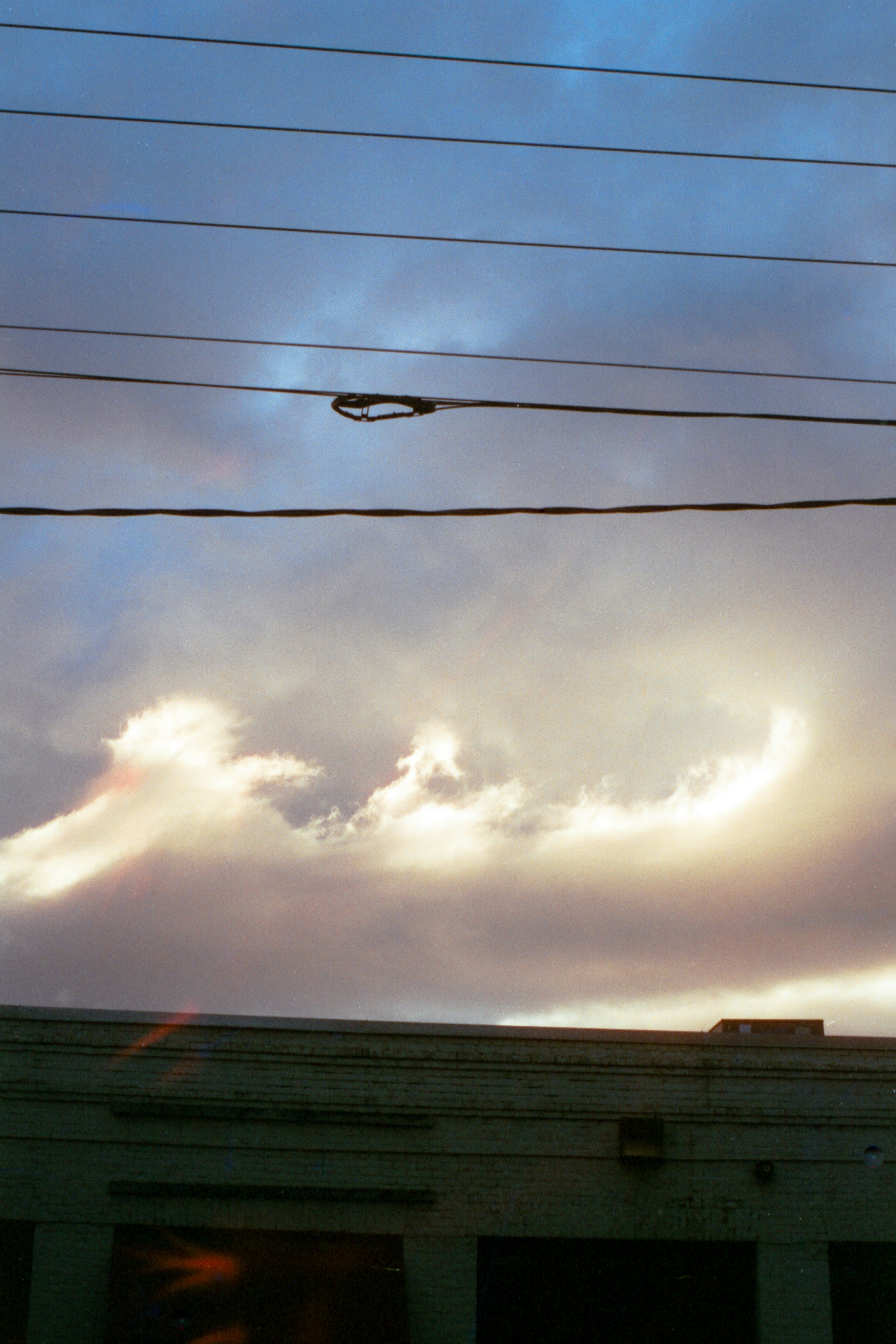 Soft clouds illuminated by the fading light, framed by silhouetted power lines against a tranquil sky.