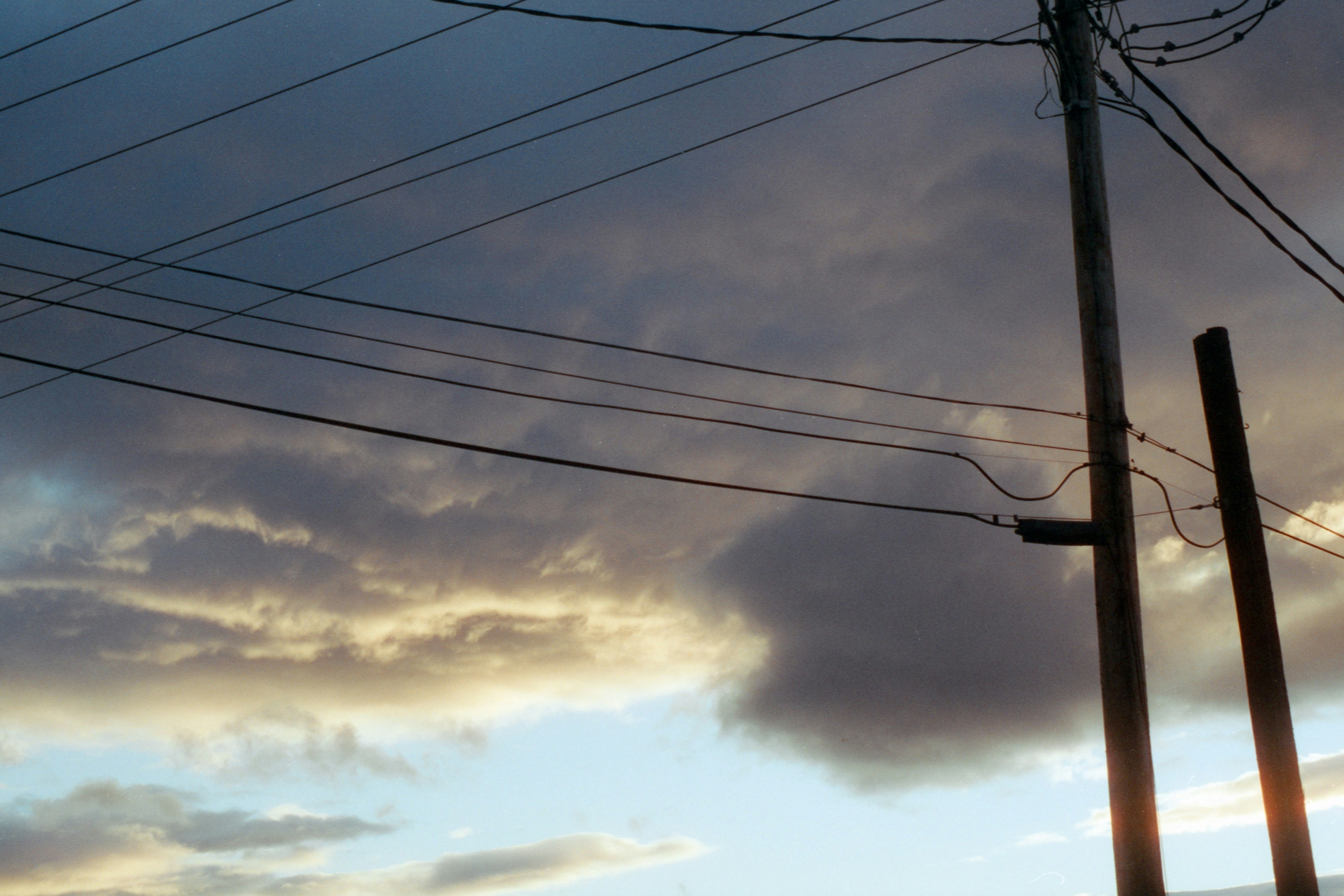 Power lines sweep across a pale dusk sky, with a weathered utility pole in the foreground.