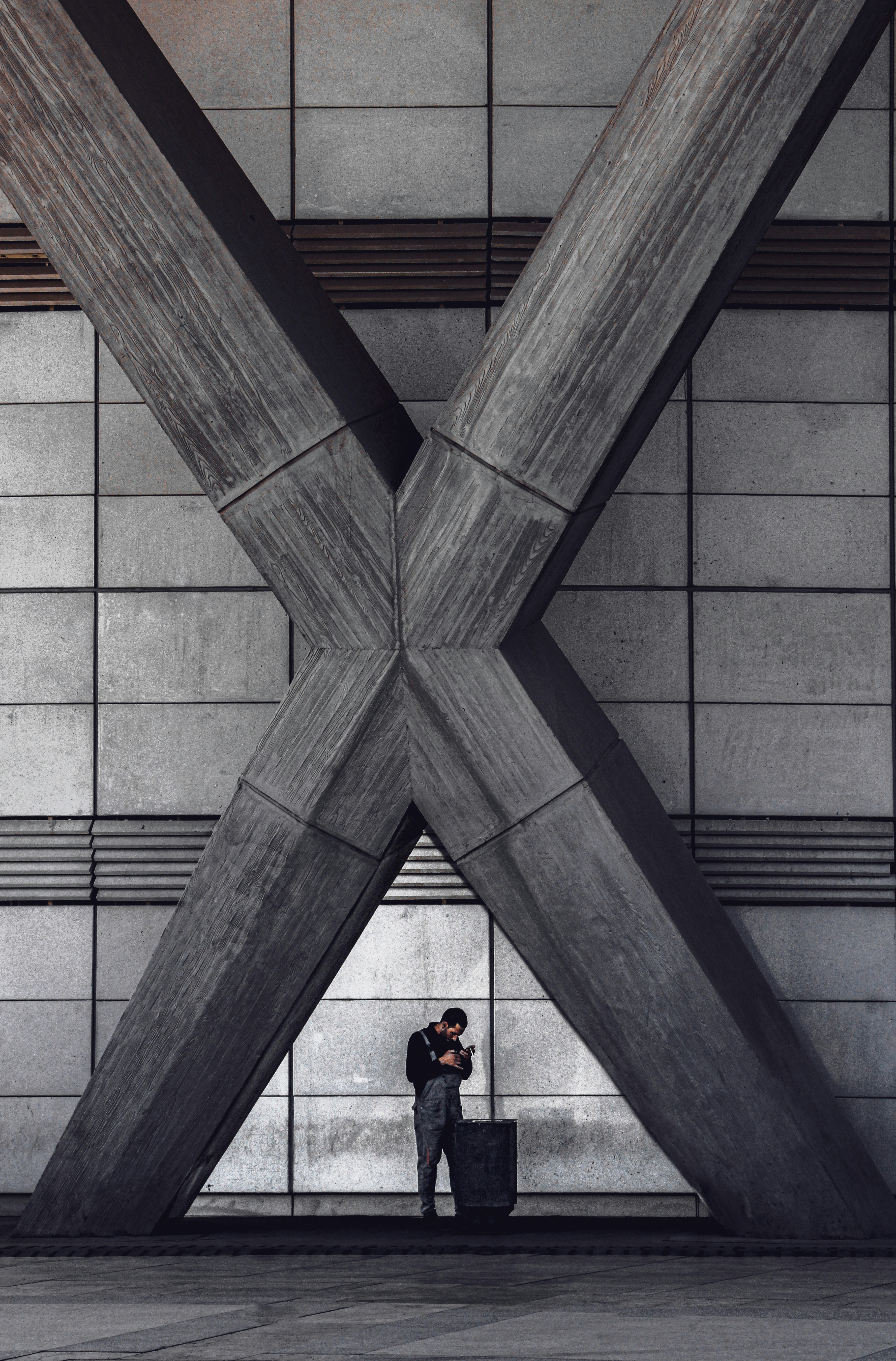 Under the Giant X: A Lone Figure Anchored by Concrete Angles