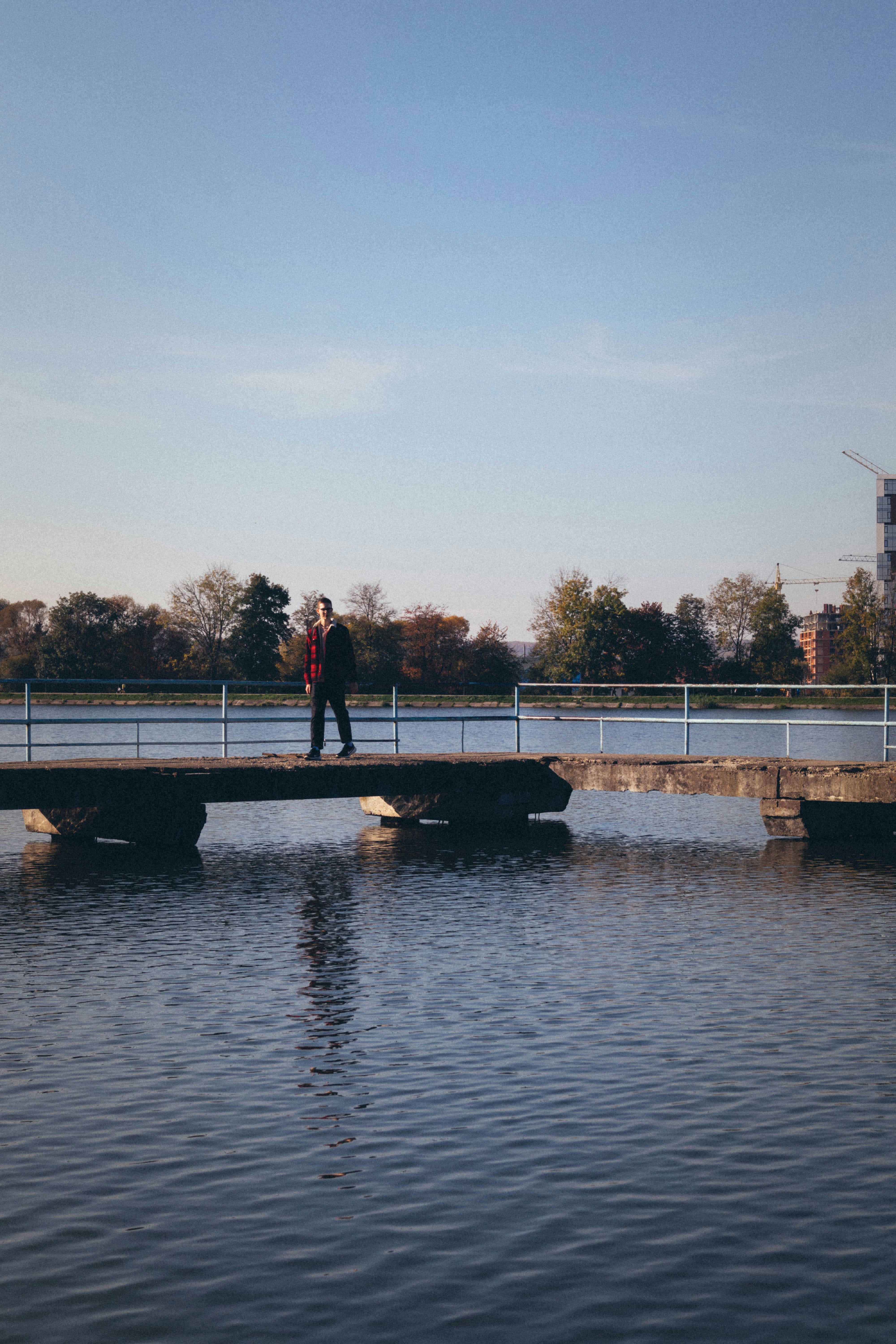 Bridge of Quiet Autumn: A Lone Figure Over a Reflective Lake