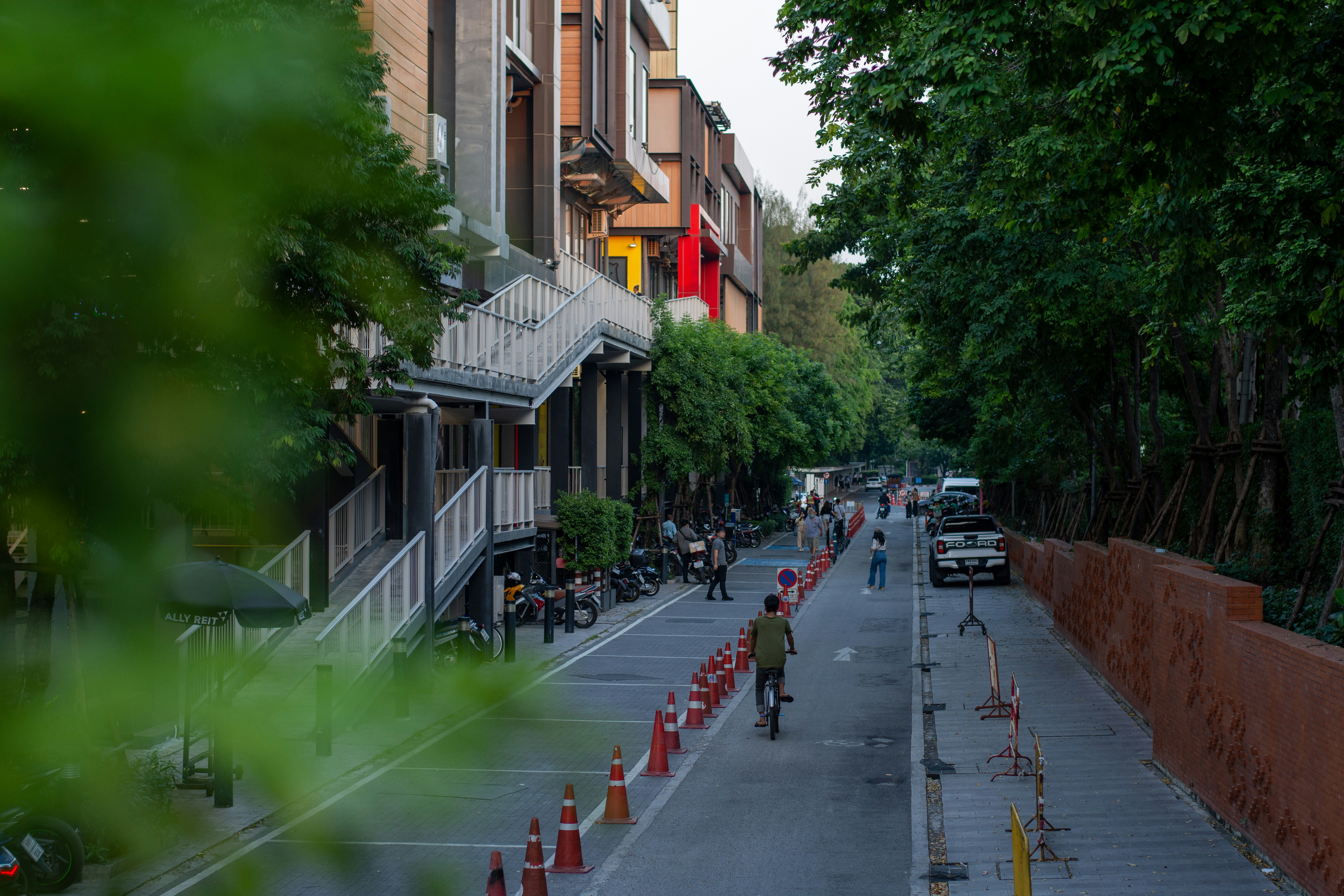 Green-Jacket Cyclist Navigates a Cone-Lined Urban Block