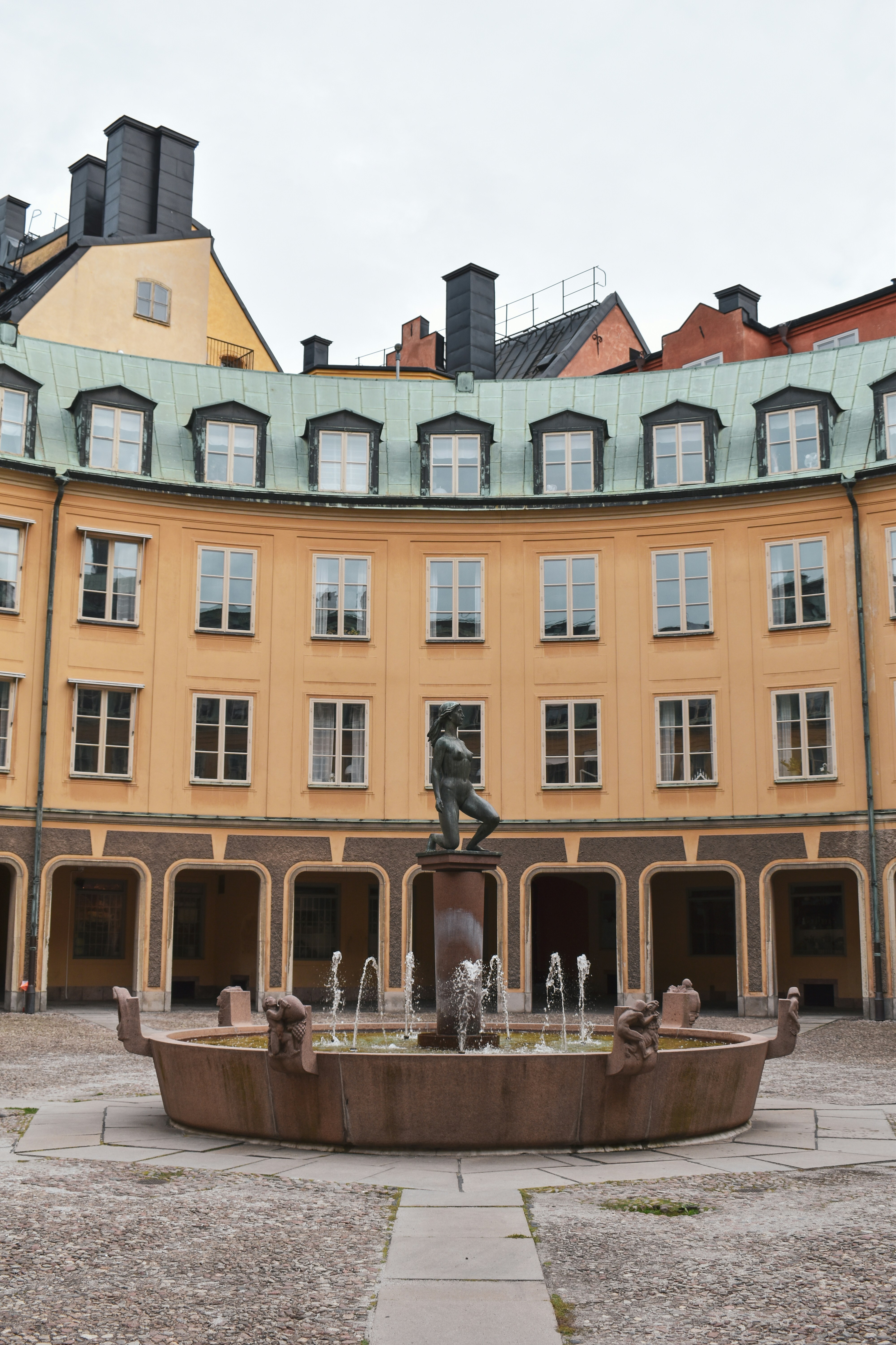 Statue Beneath a Peach Arc: Circular Fountain in a Sunlit Courtyard
