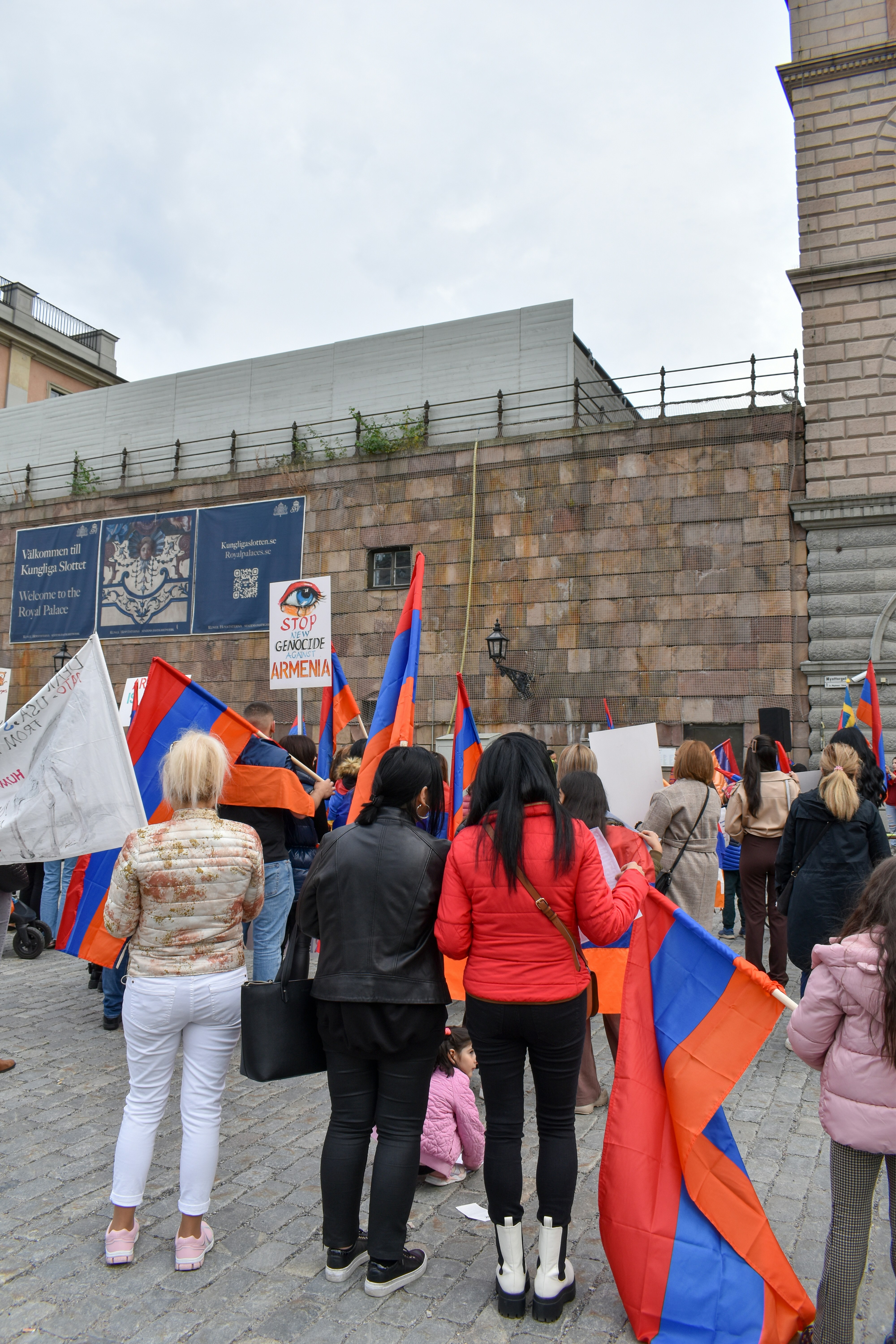 Crowd Rally with Armenian Flag Banners before a Historic Stone Wall