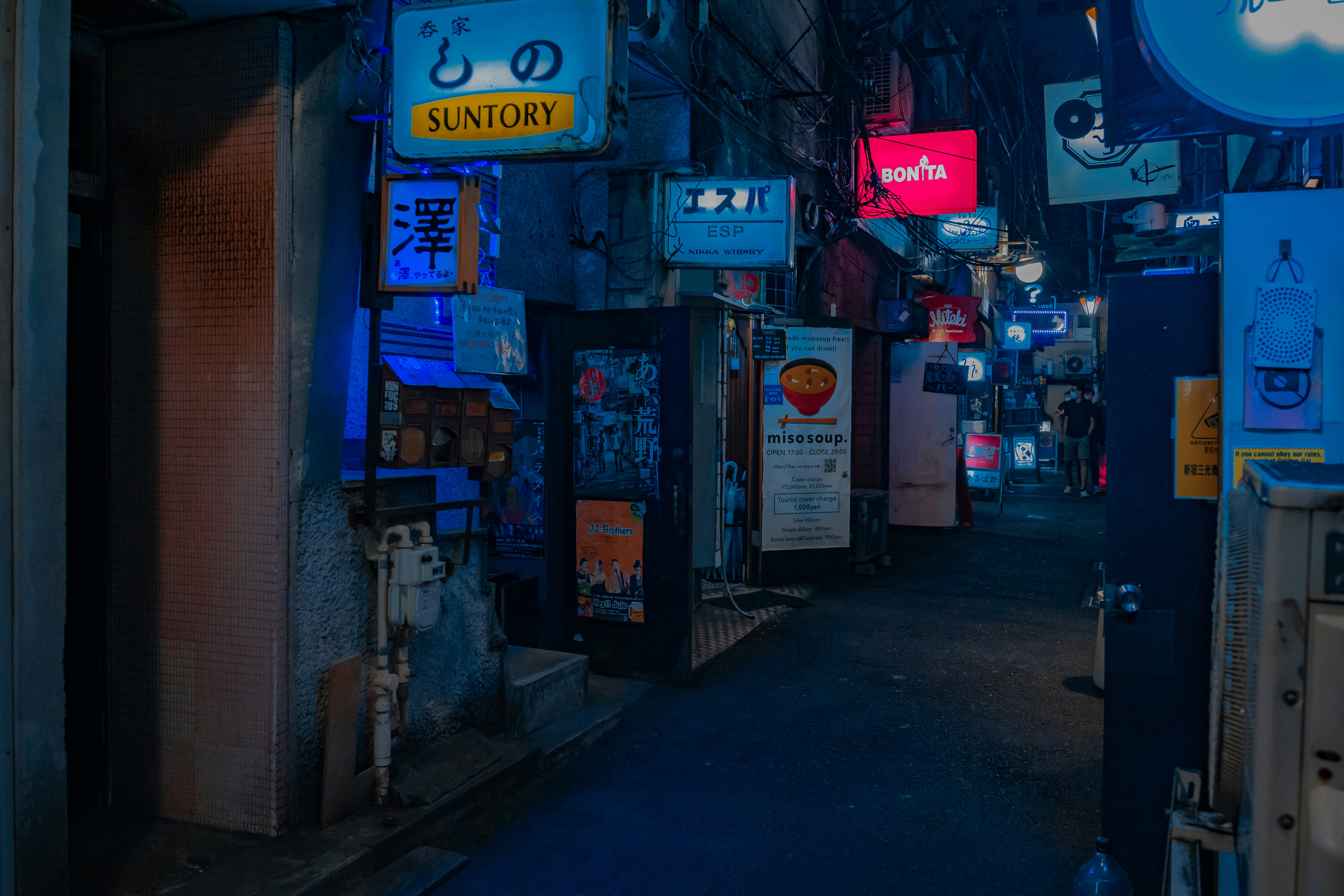 A street with signs and posters on the wall photo – Free Road Image on ...