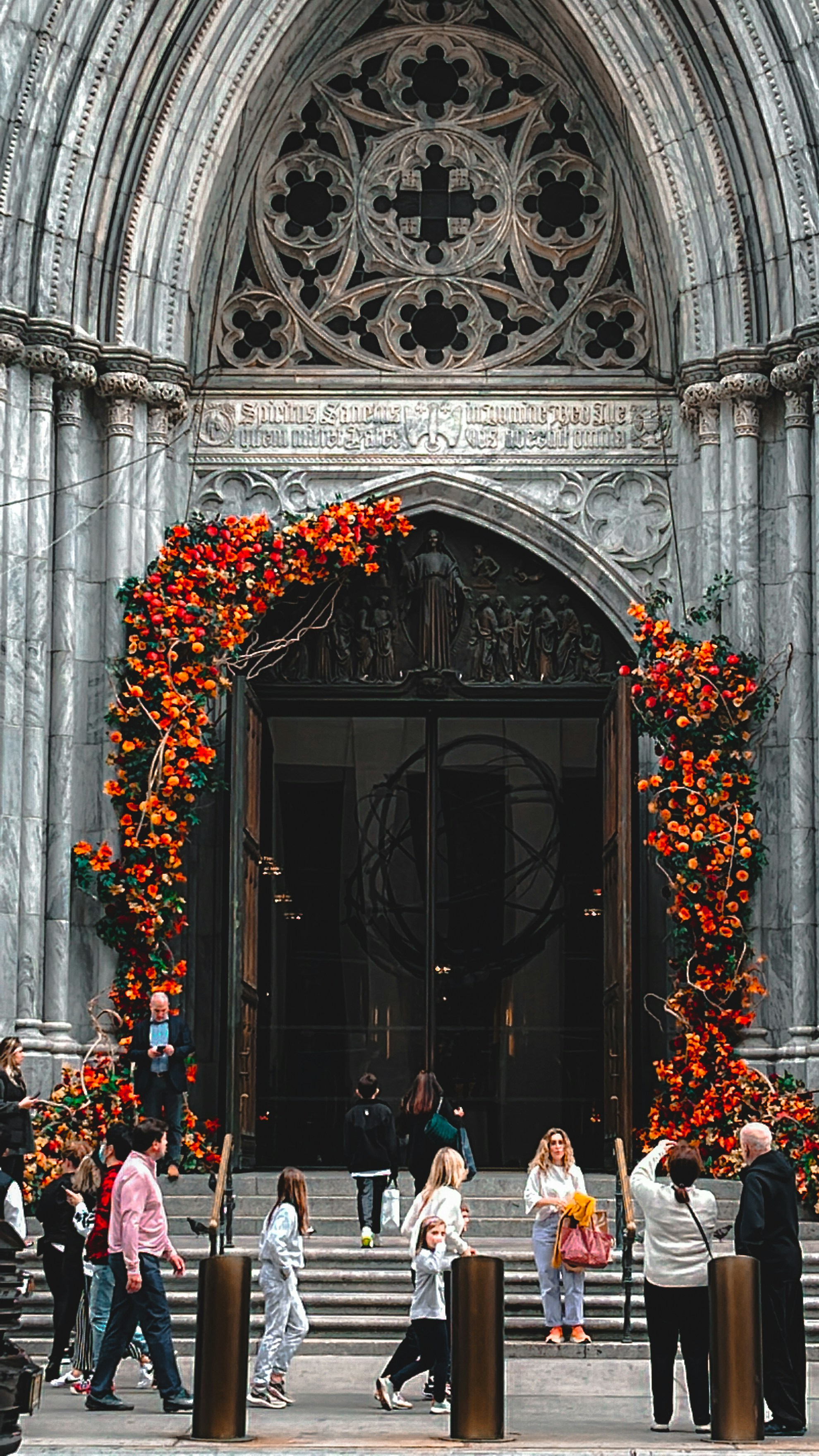 A group of people standing outside a building with a large arched ...