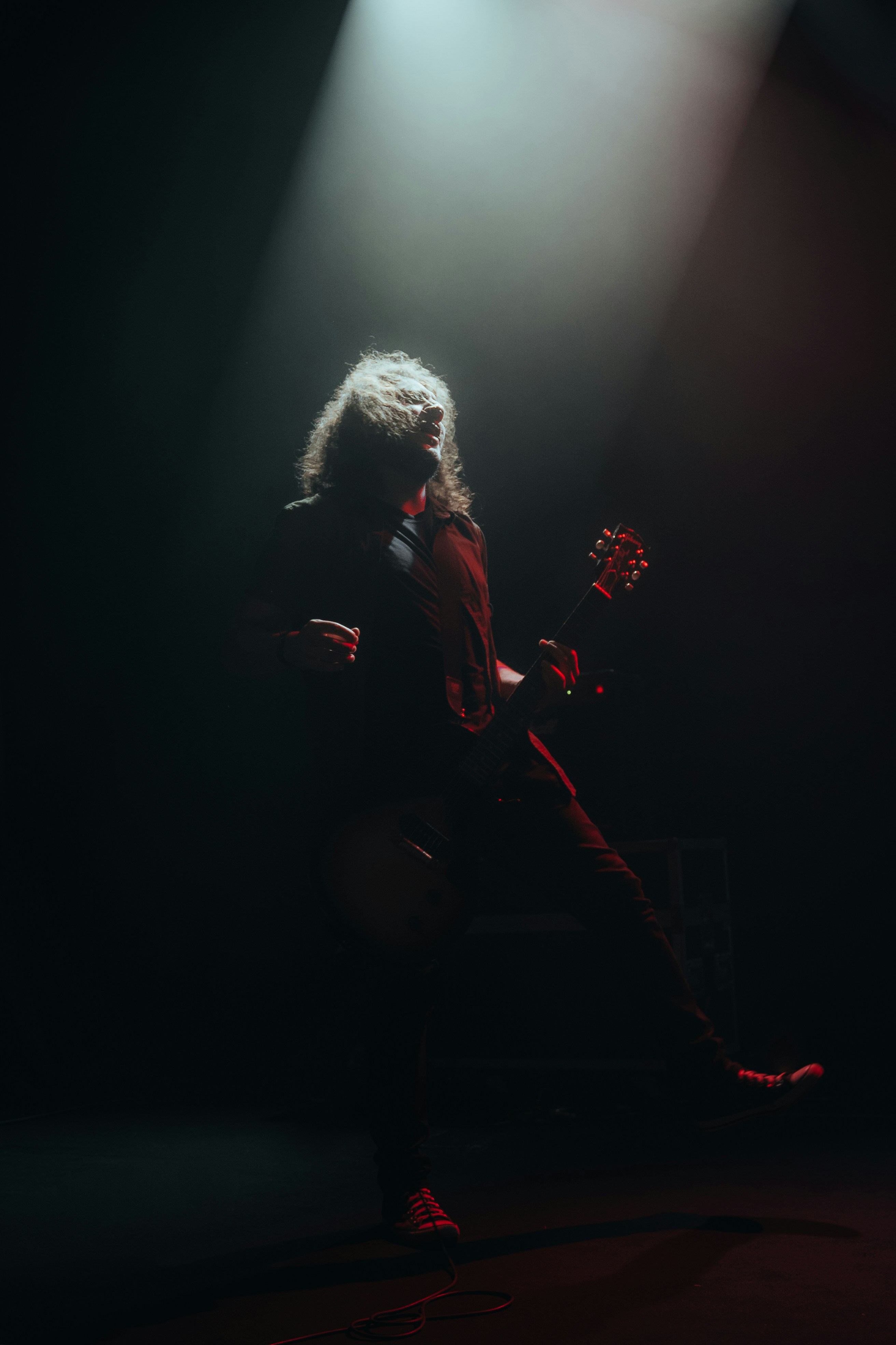 Crimson Halo: Silhouette of a Guitarist Under a Lone Spotlight