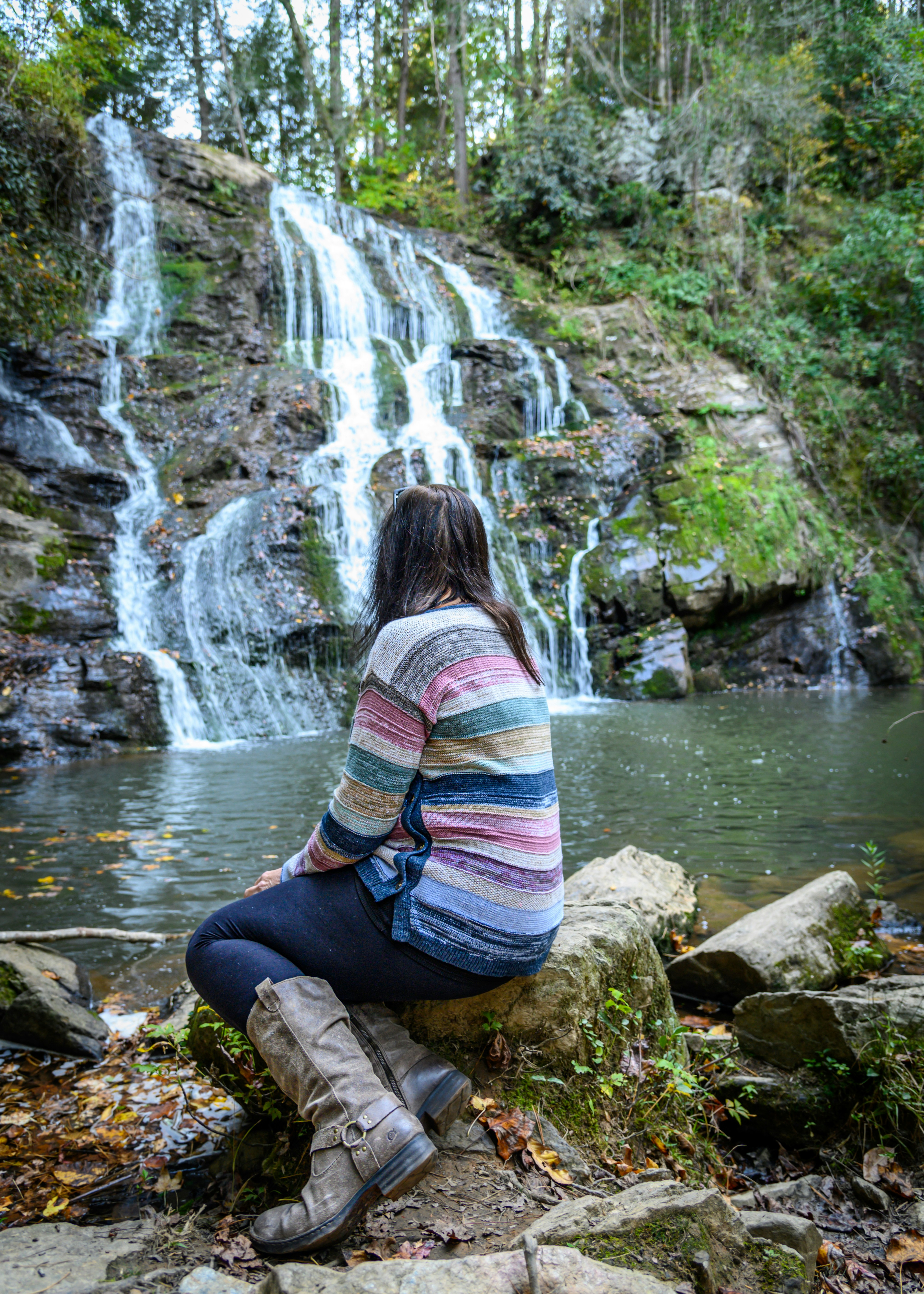 Foto Un hombre sentado en las rocas junto a una cascada – Imagen ...