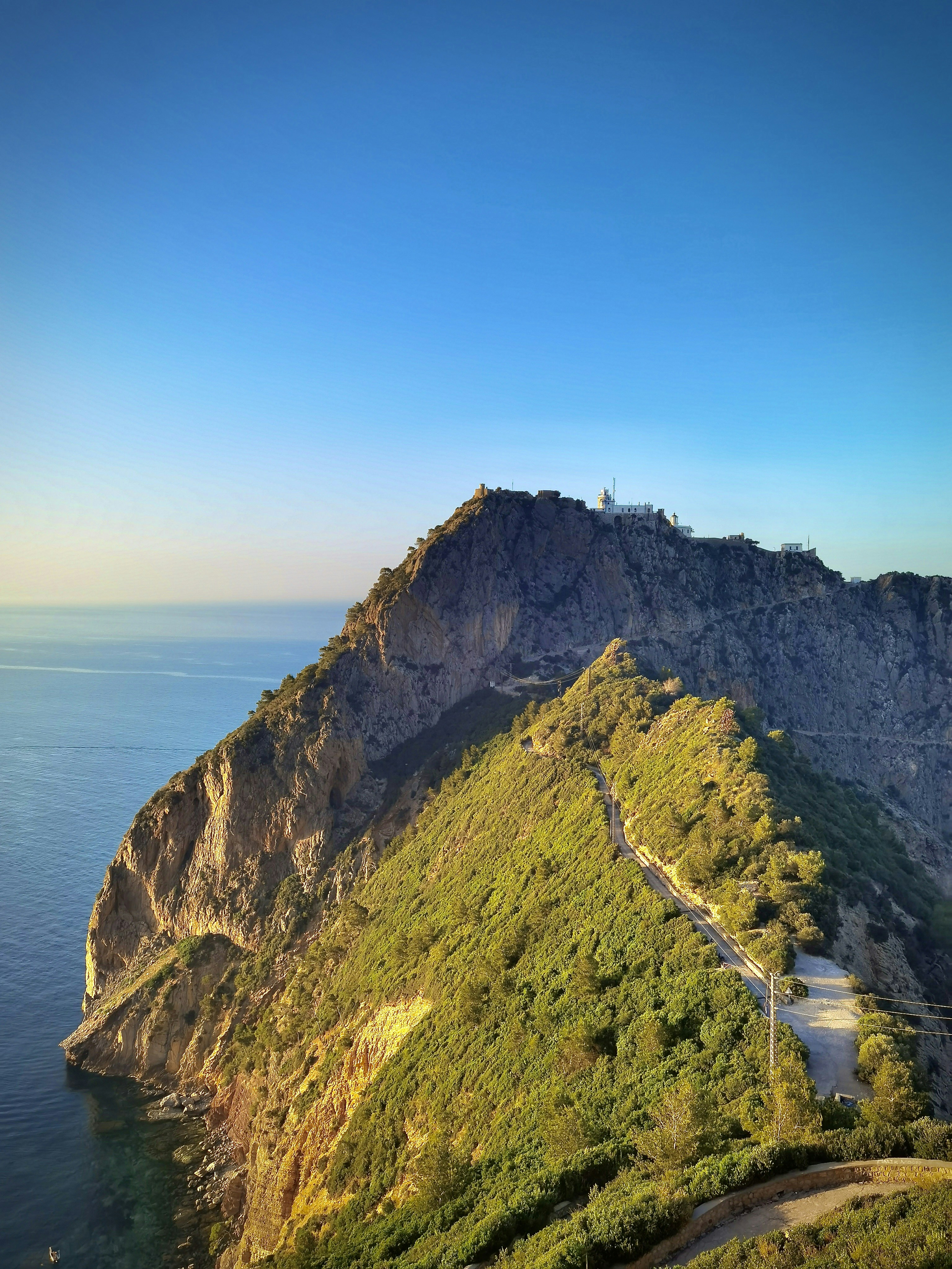 Foto Una colina con un camino y árboles junto al agua – Imagen Tessala ...