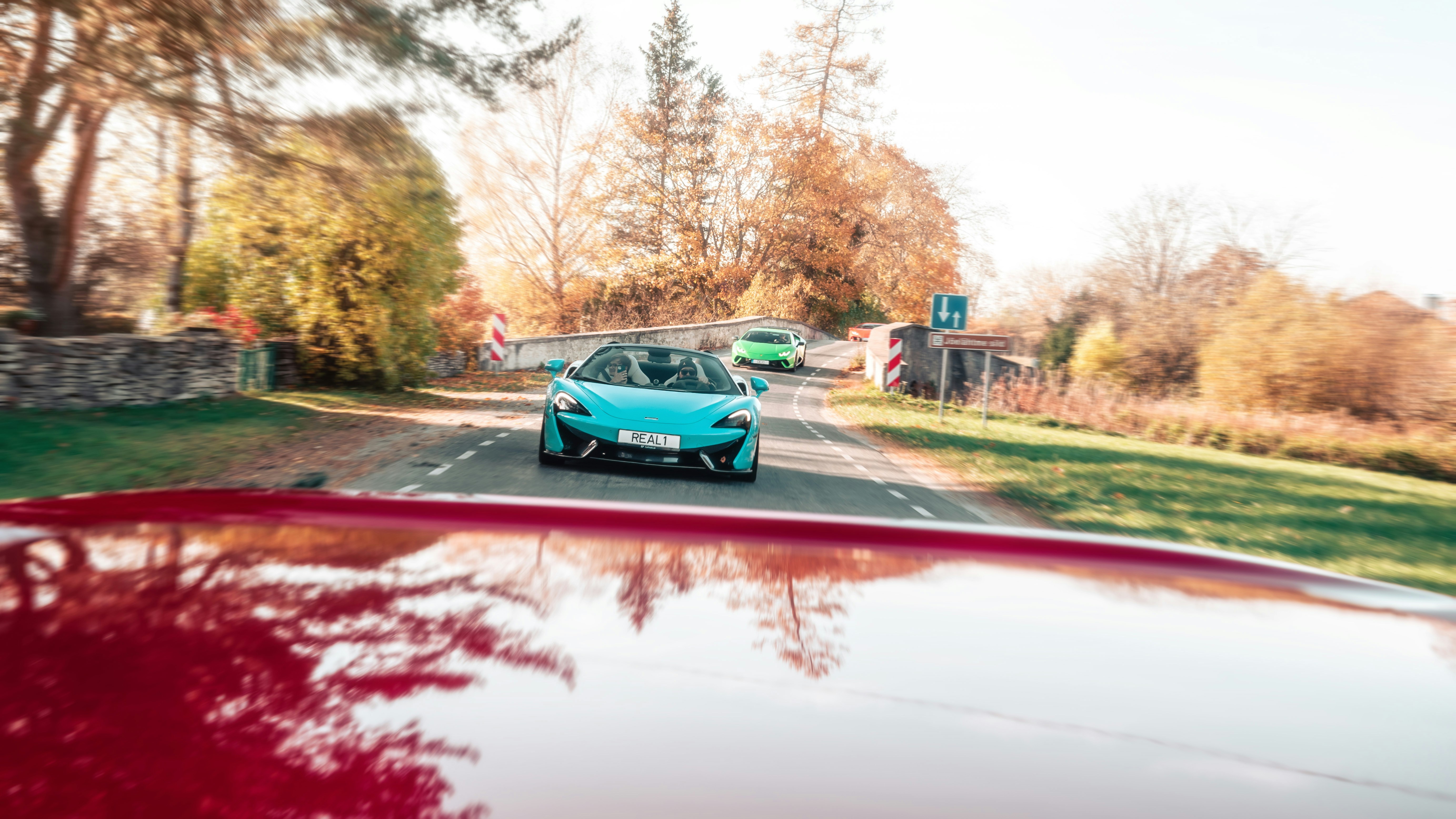 Blue sports coupe carving through a sunlit countryside lane