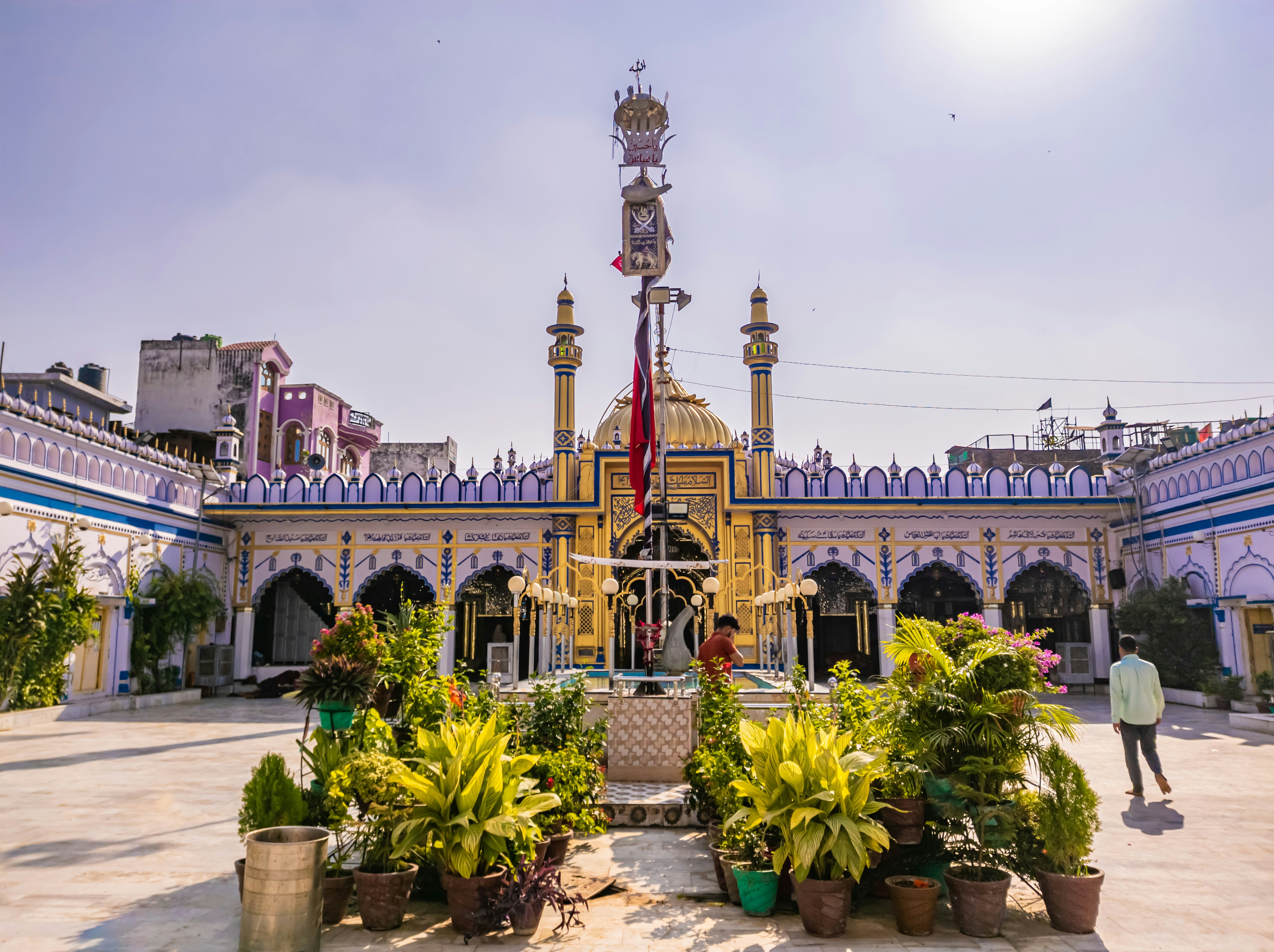 Vibrant temple courtyard adorned with lush greenery and intricate architecture, showcasing a blend of cultural elements. A serene atmosphere invites visitors to explore.