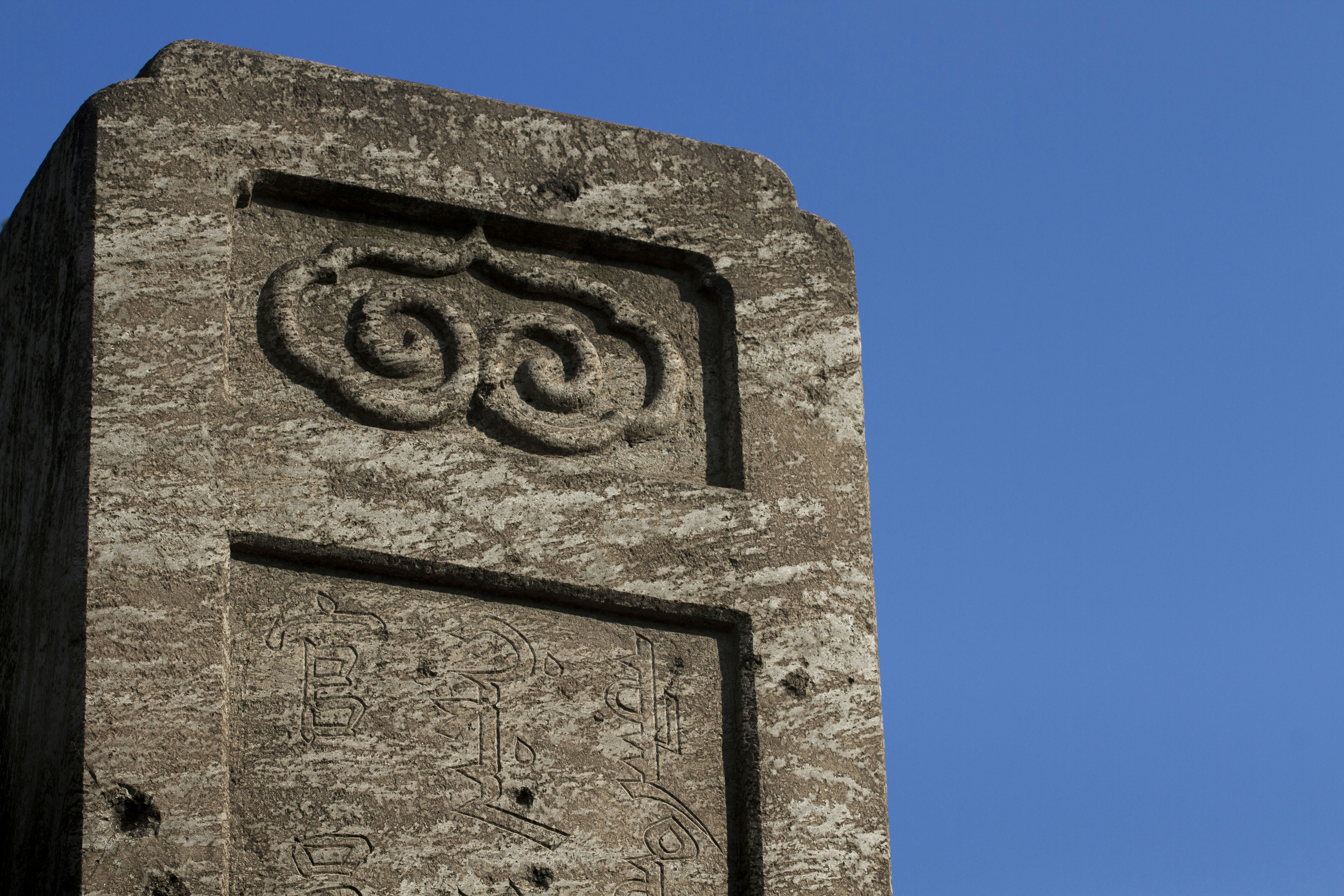 Spiral relief on a weathered stele under a cobalt sky