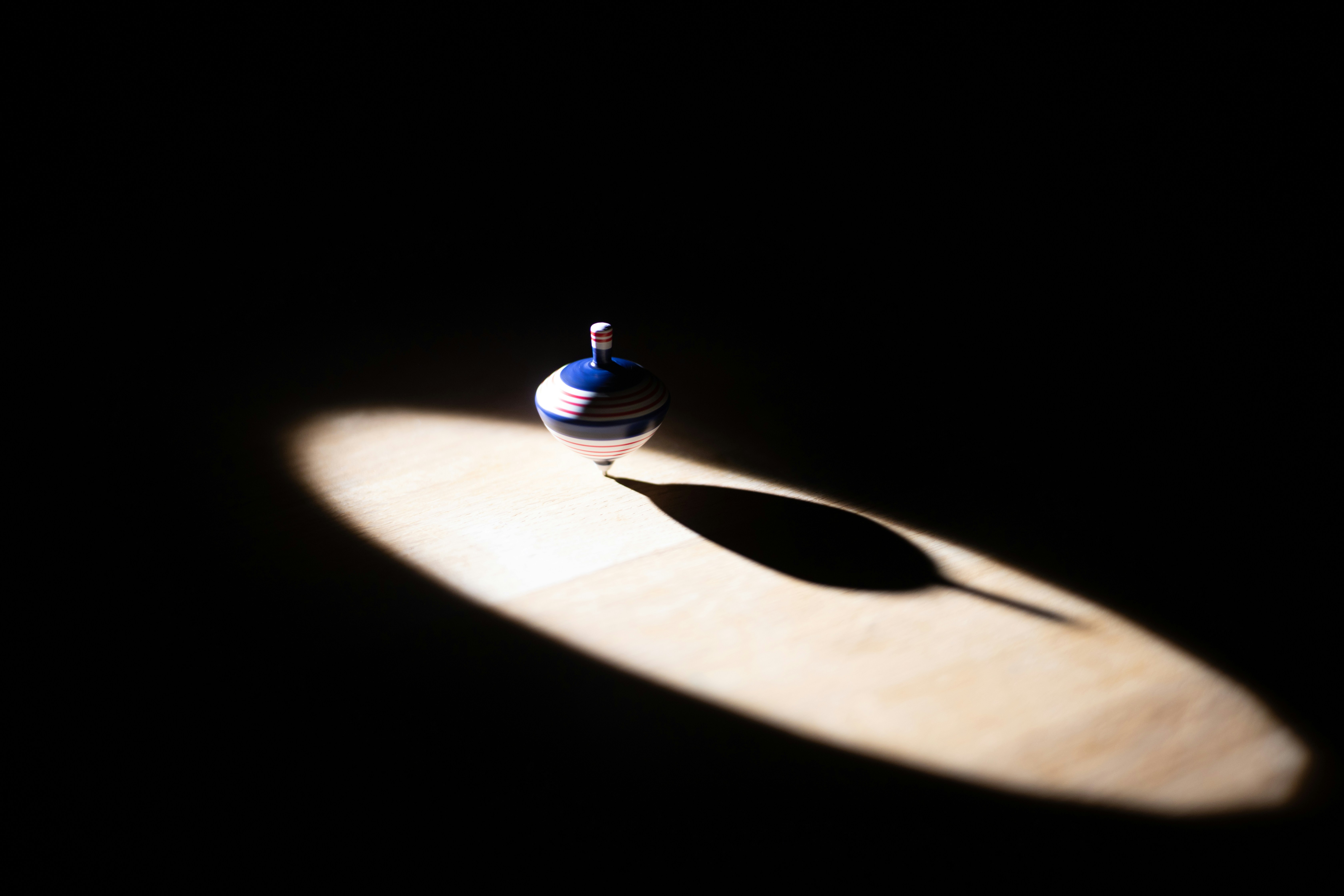 Blue-Striped Spinning Top in a Lone Spotlight on a Wooden Stage