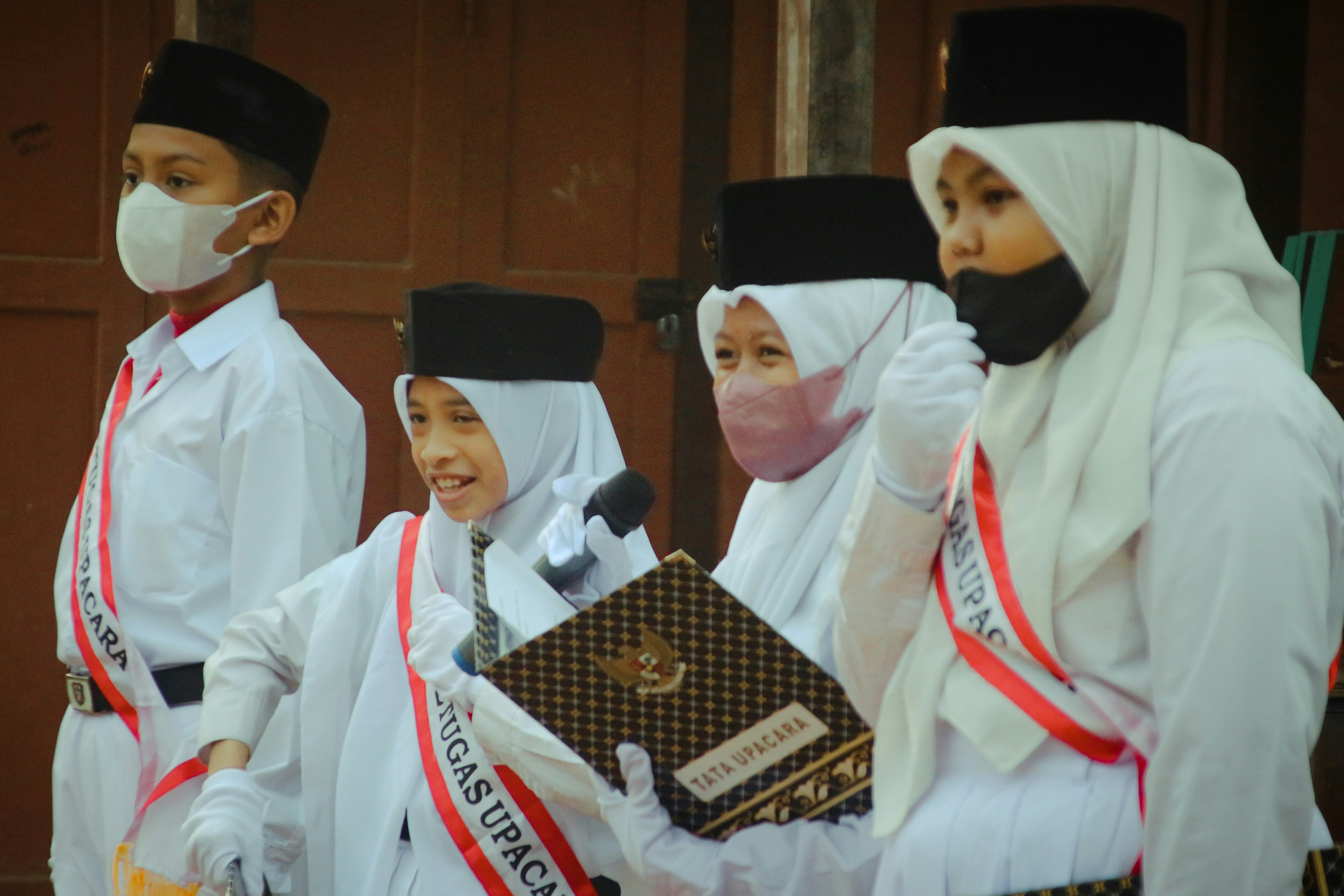 Four children in traditional attire, engaged in a ceremonial event, showcasing their roles with confidence and joy.