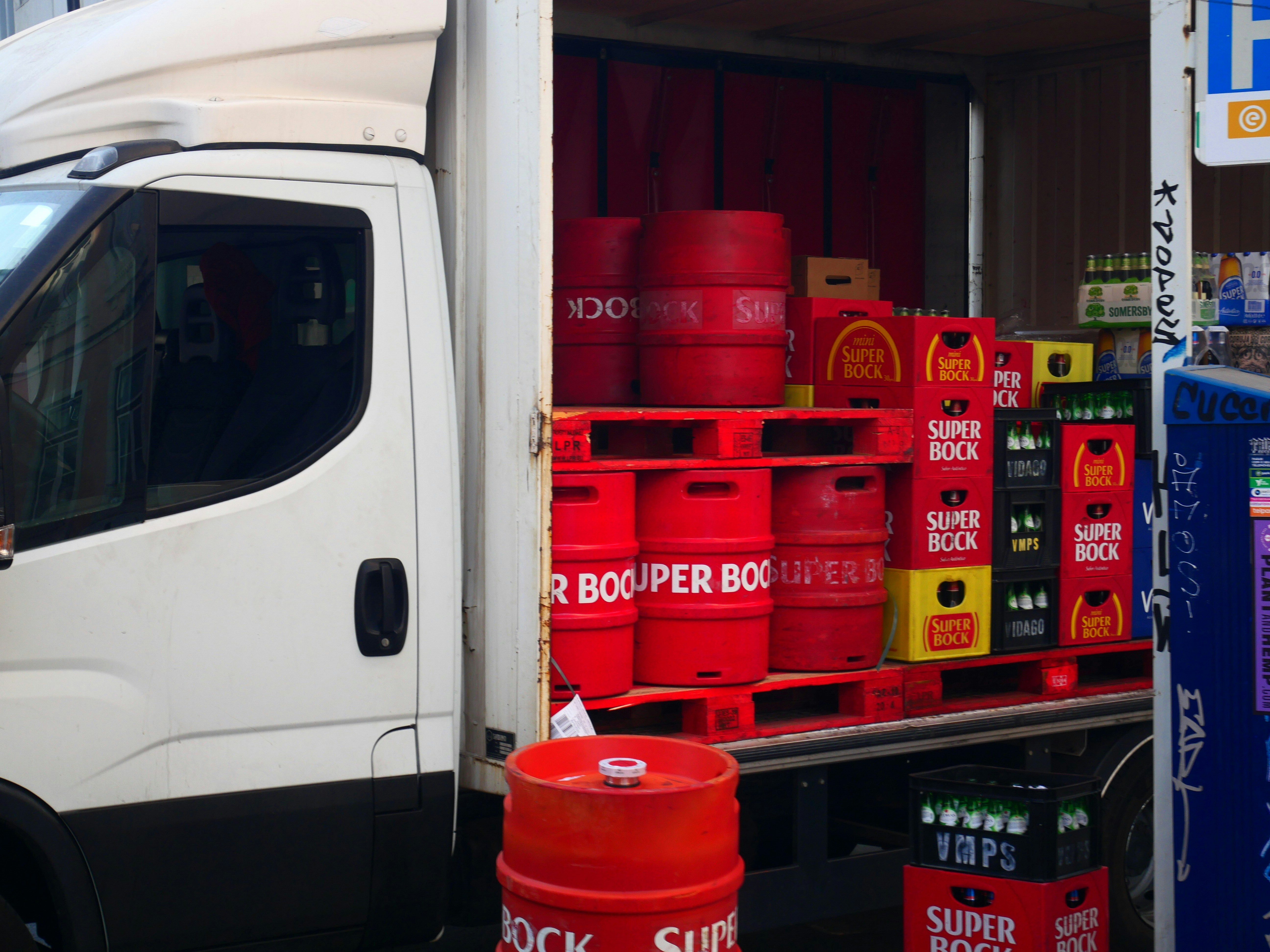 Delivery truck filled with crates and kegs of Super Bock beer, showcasing a busy beverage distribution scene.