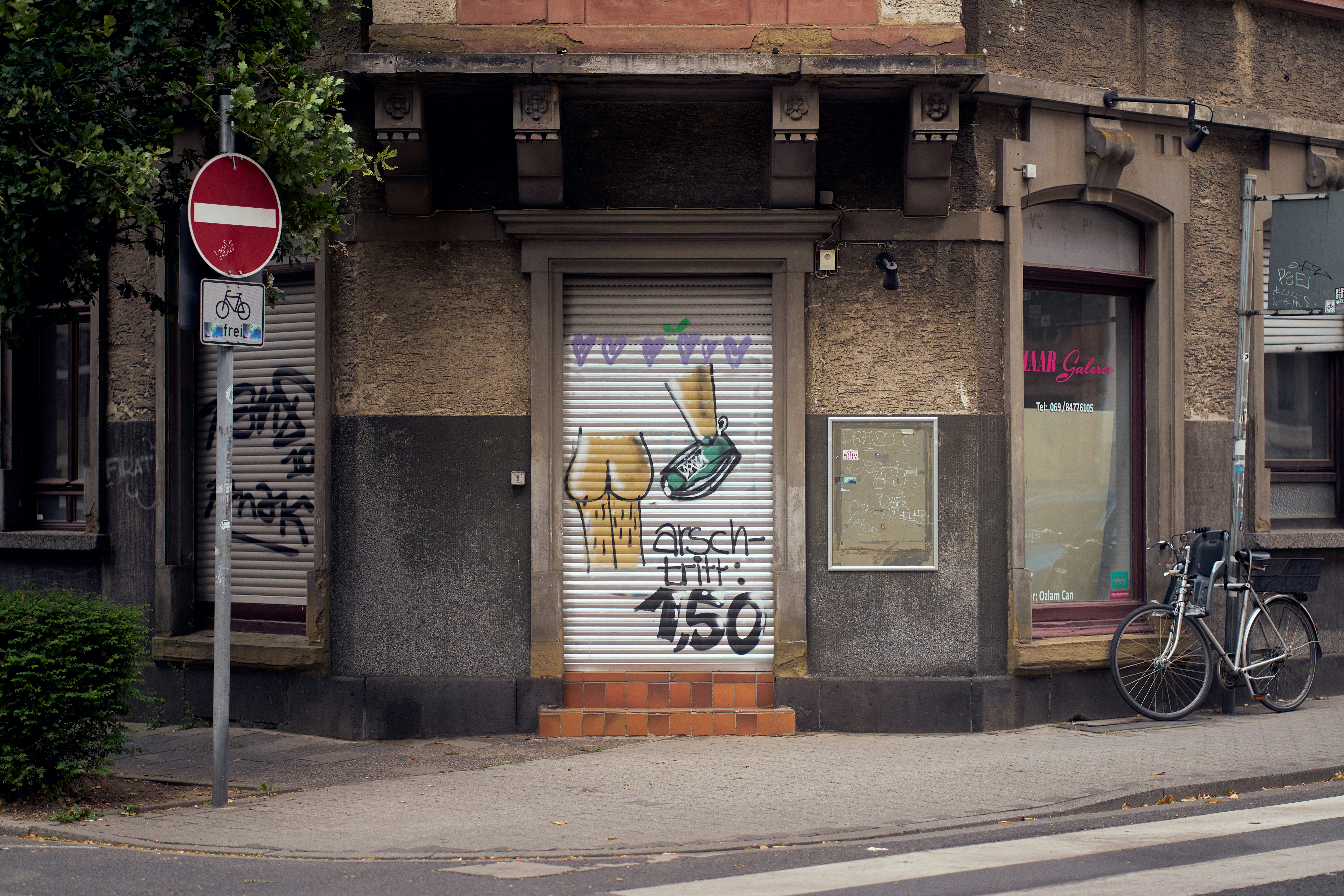 Graffiti-covered doorway on an old urban building with a bicycle leaning against the wall.