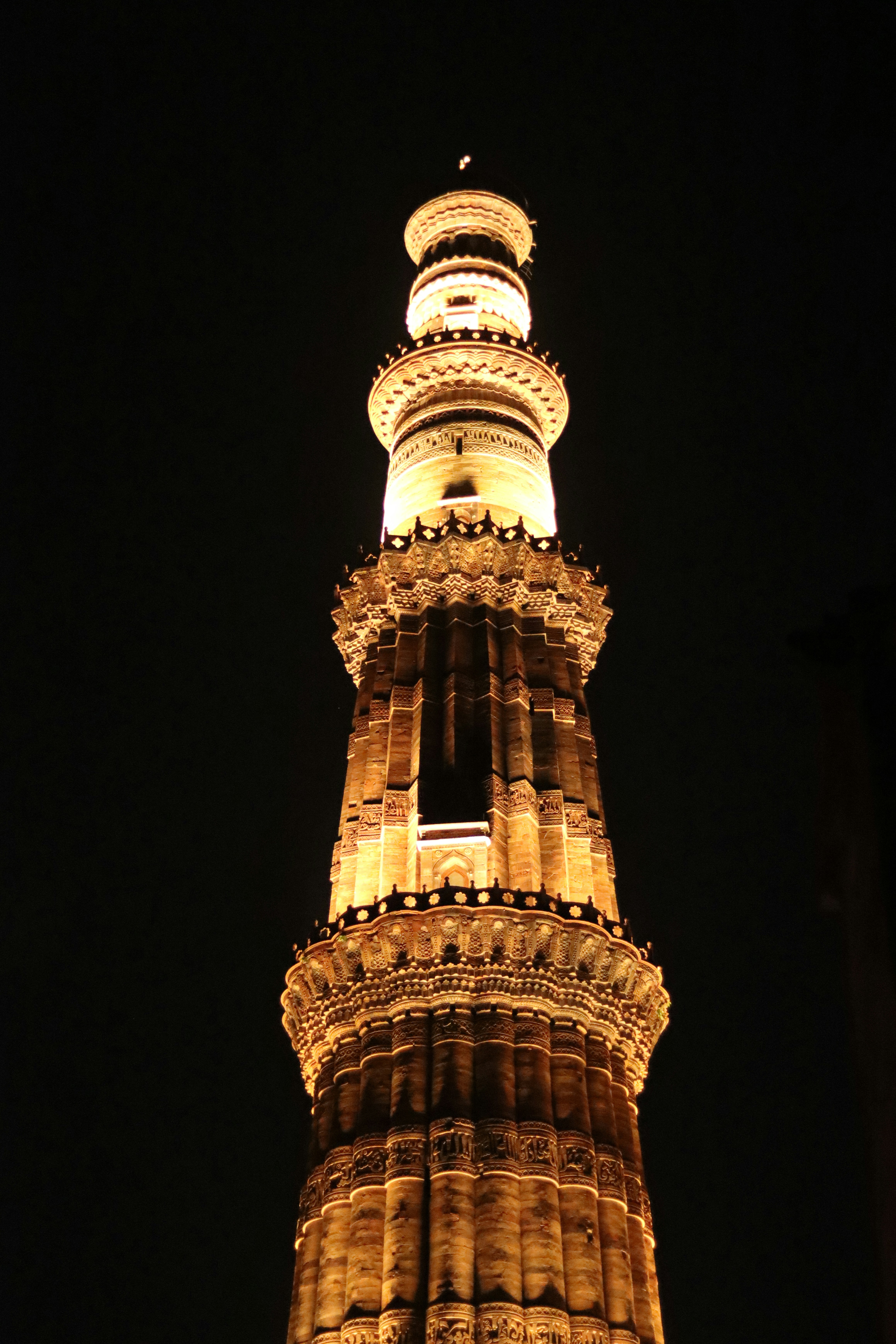 Night-lit Qutub Minar: Warm Carved Tiers Reaching the Dark Sky