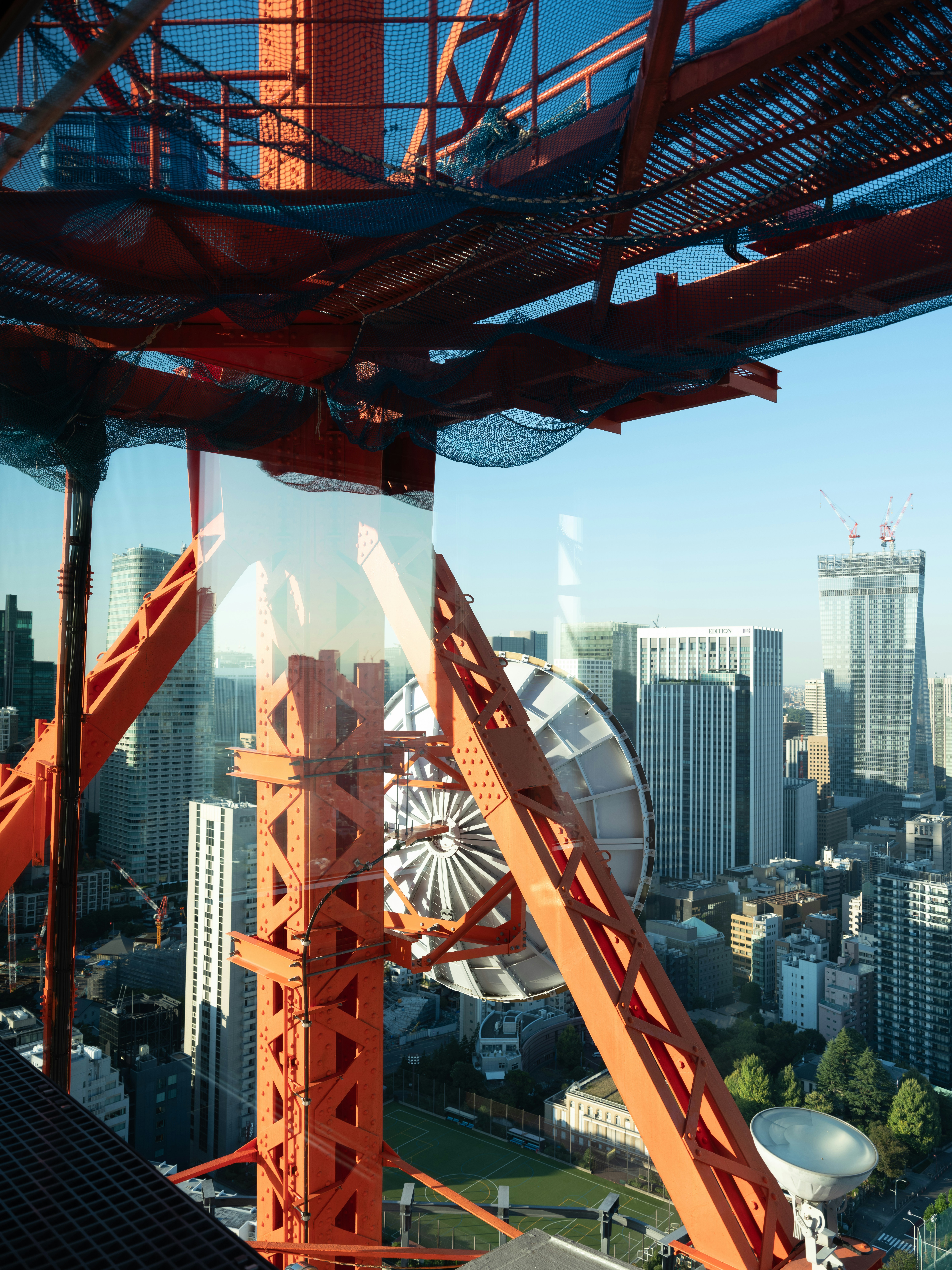 Crimson Skeleton Over the City: A Circular Turbine Framed by Red Structural Beams