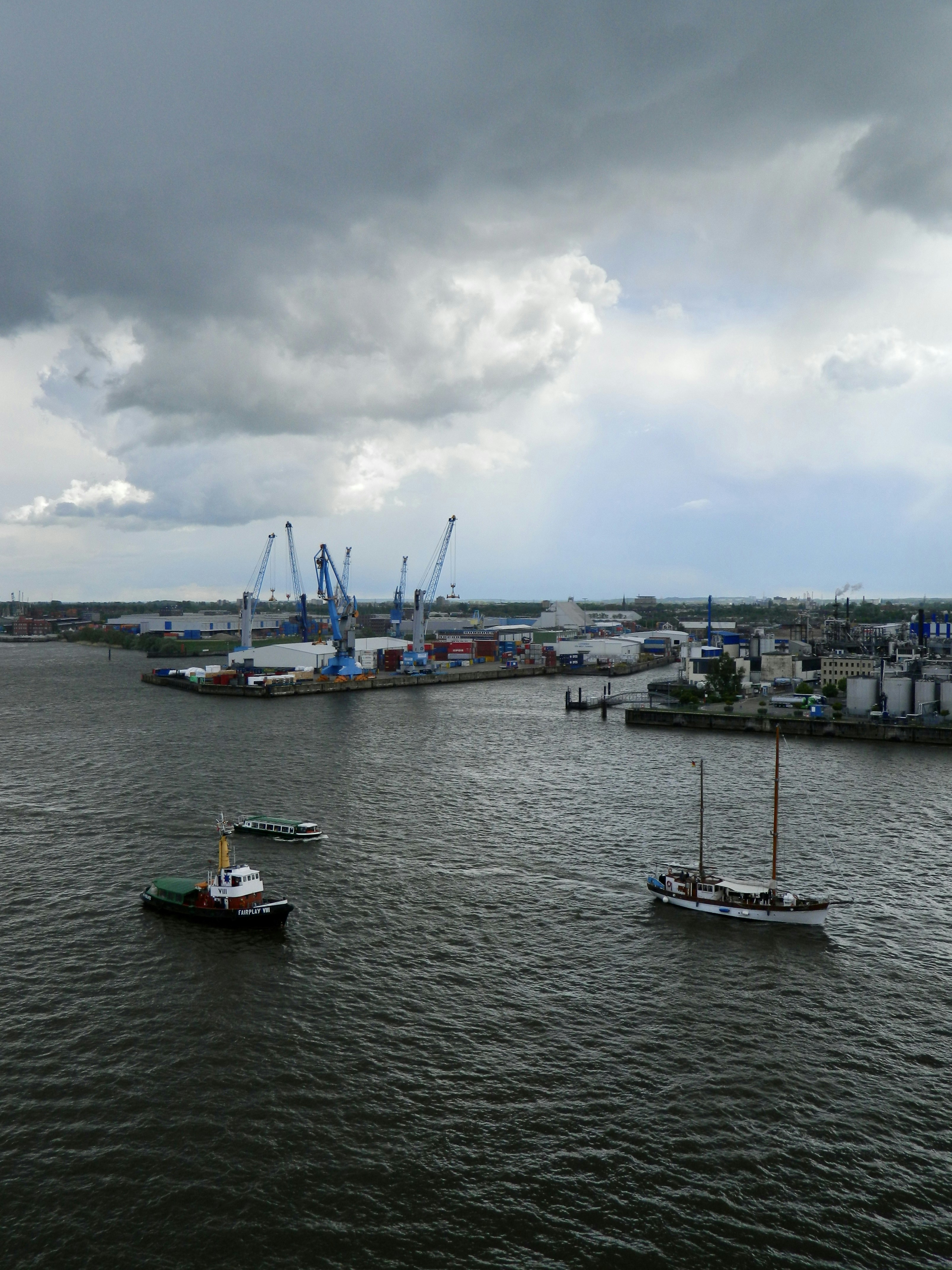 Boats navigate the waterway near a bustling harbor, framed by dramatic cloud formations overhead.