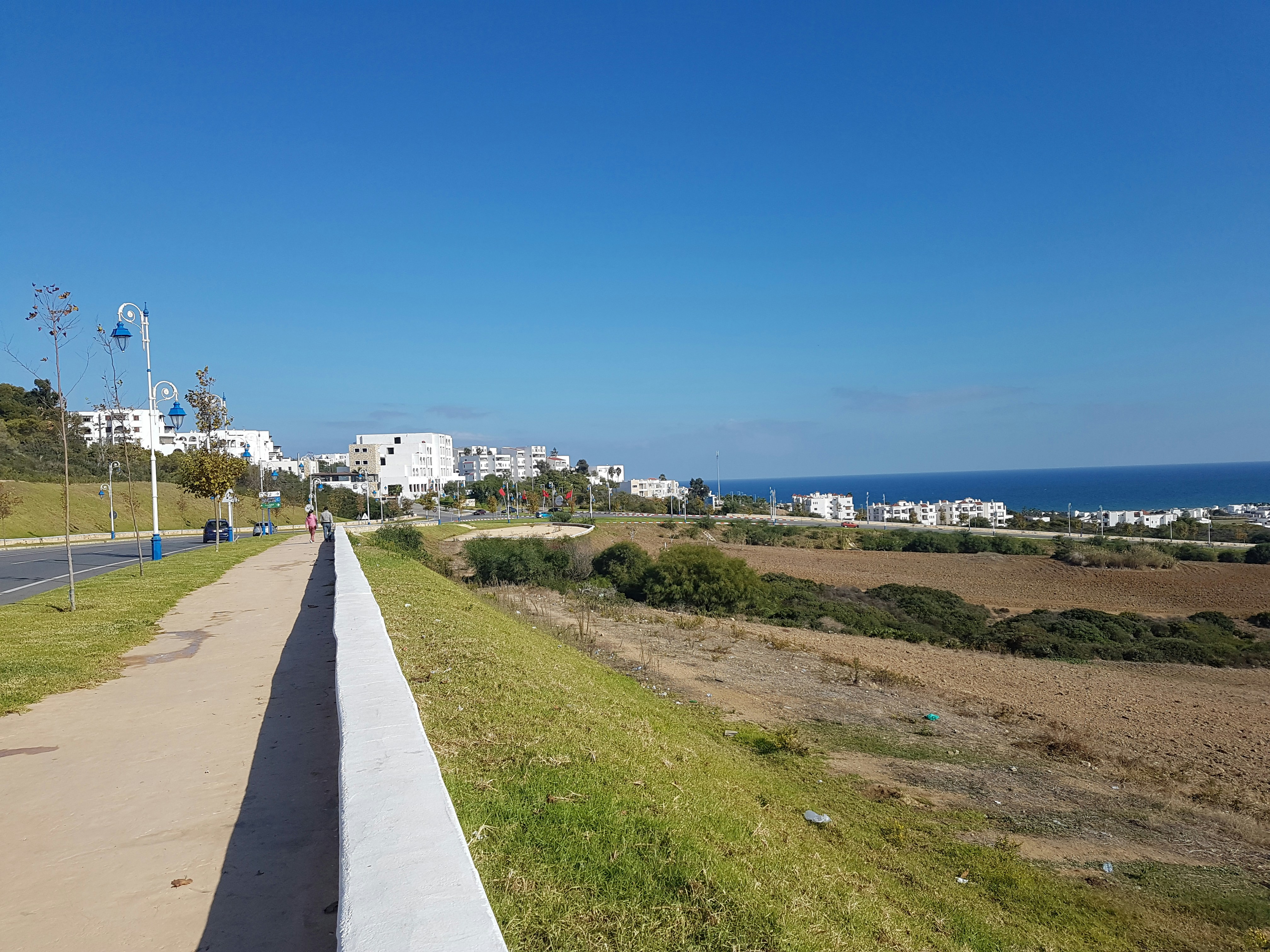 A road with grass and trees by a body of water photo – Free Plage de ...