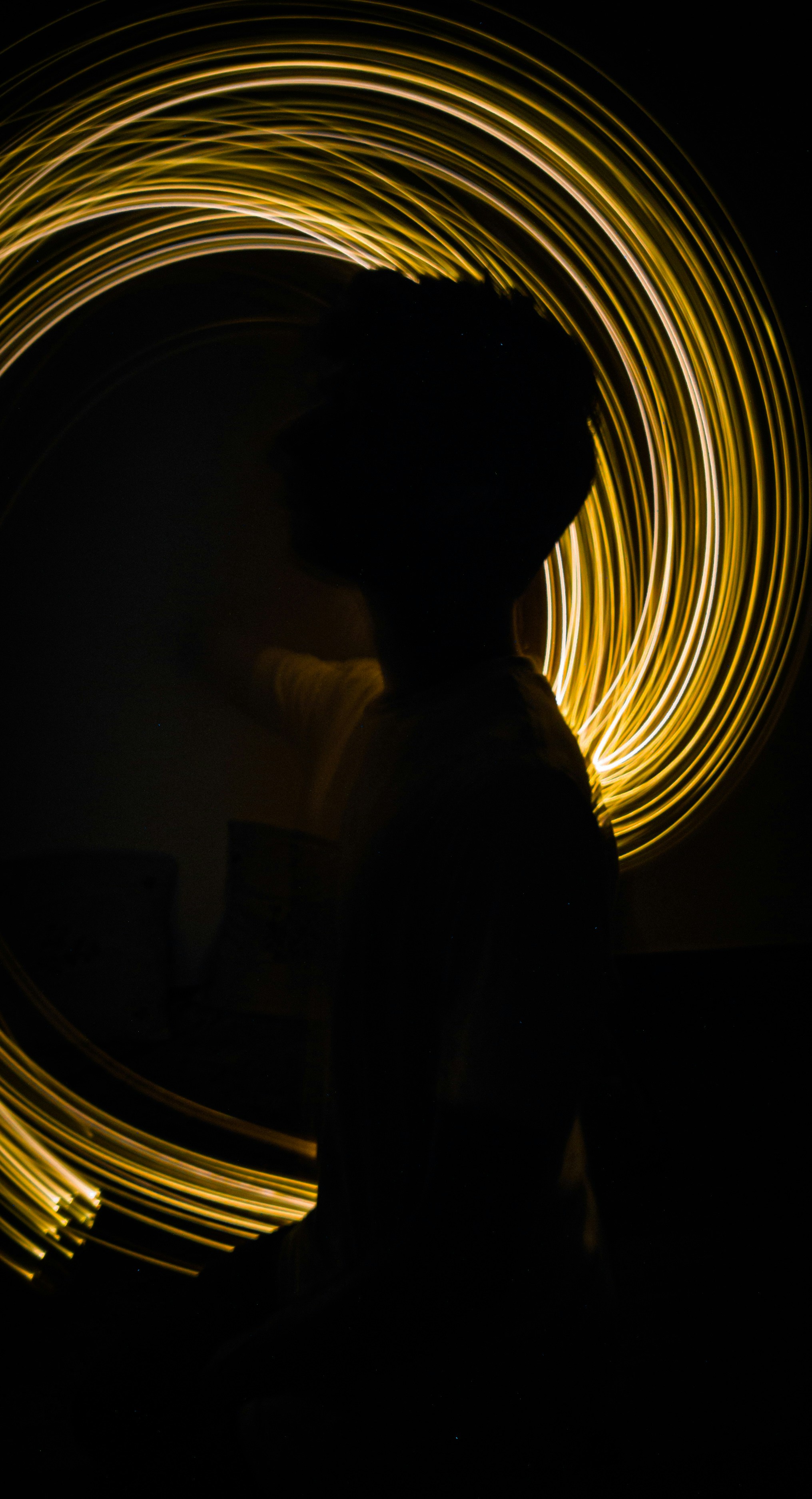 Silhouette of a person in motion surrounded by swirling golden light trails. The dynamic composition captures the essence of movement and creativity.