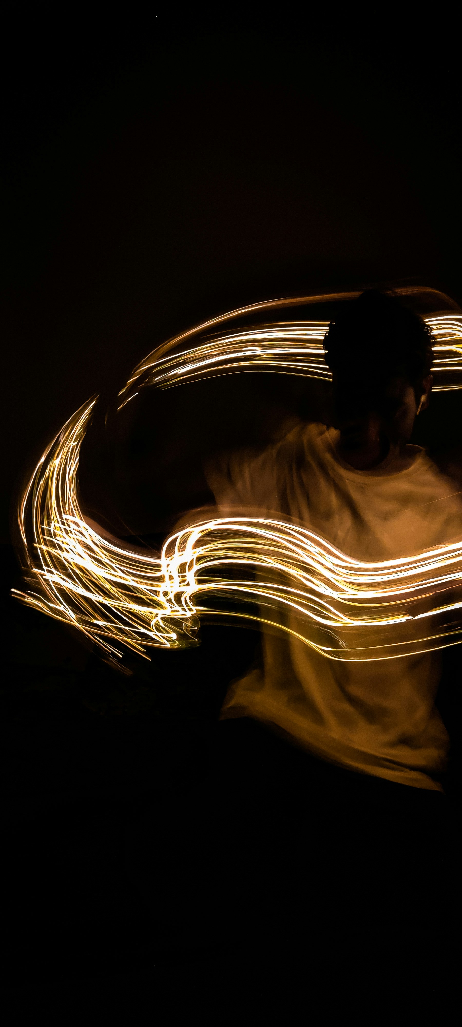 A figure swirls light trails against a dark backdrop, capturing the essence of movement and creativity. The dynamic patterns evoke a sense of rhythm and energy.