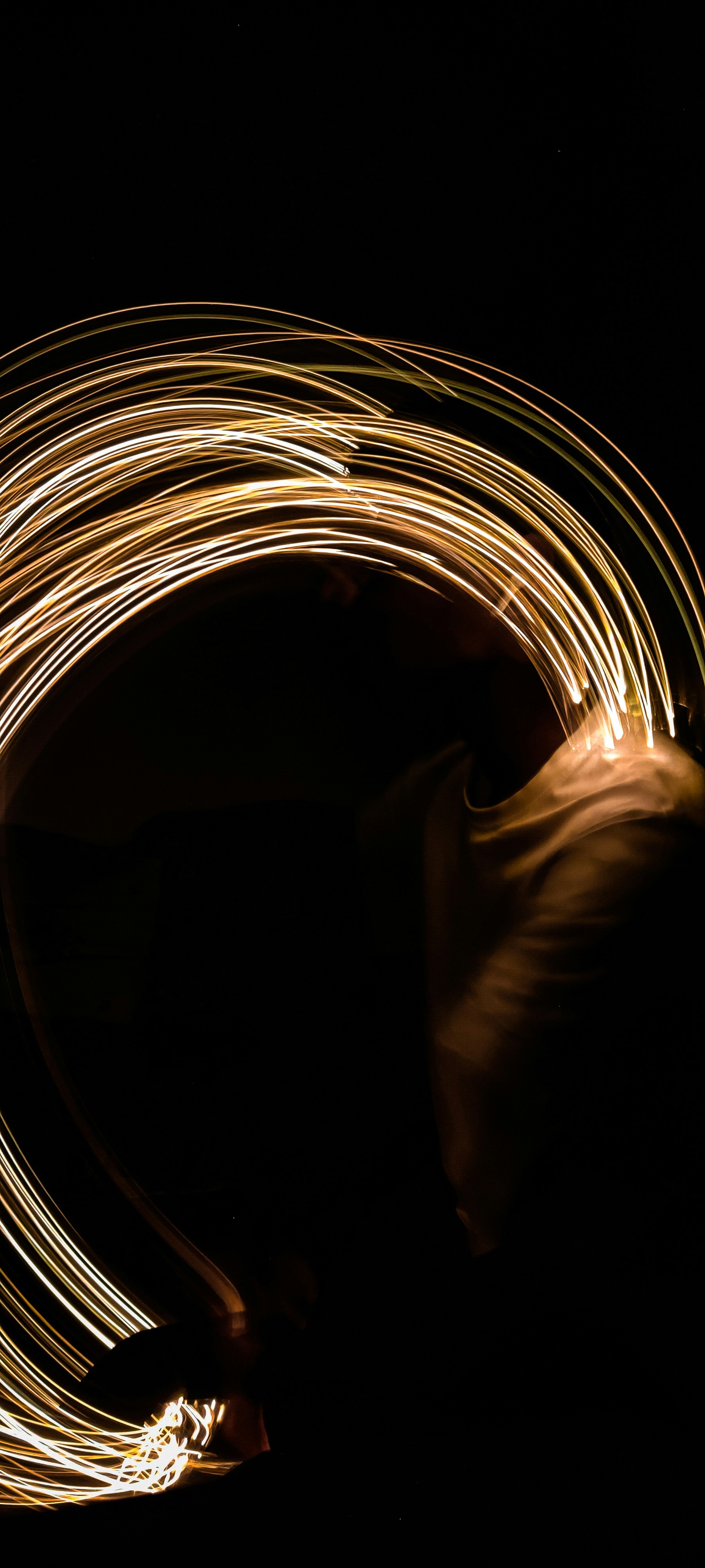 Dynamic light trails swirl around a figure in motion, creating a mesmerizing contrast against the dark backdrop.