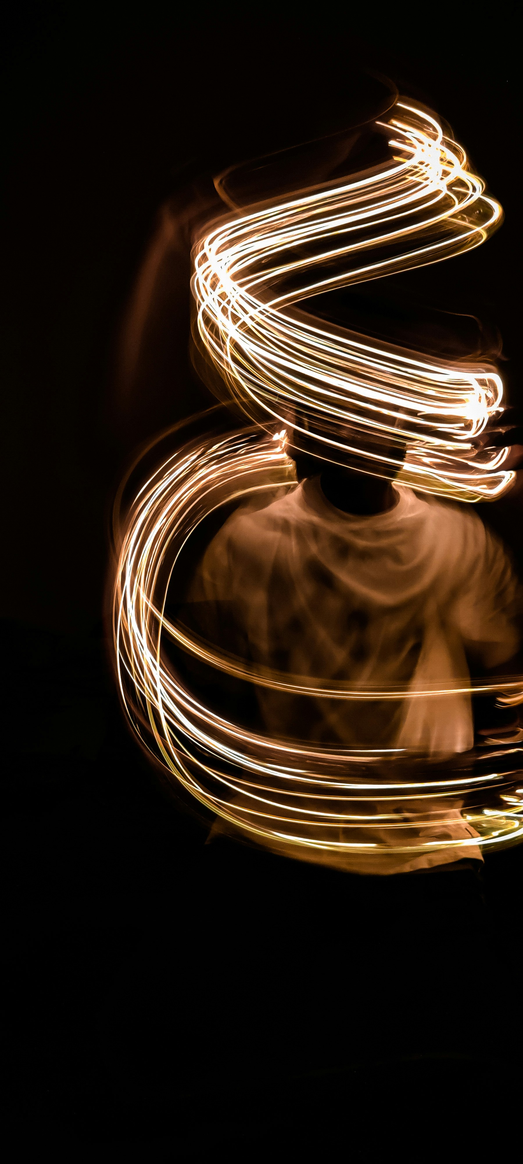 Dynamic light trails swirl around a figure in motion, creating an abstract representation of energy and creativity against a dark backdrop.