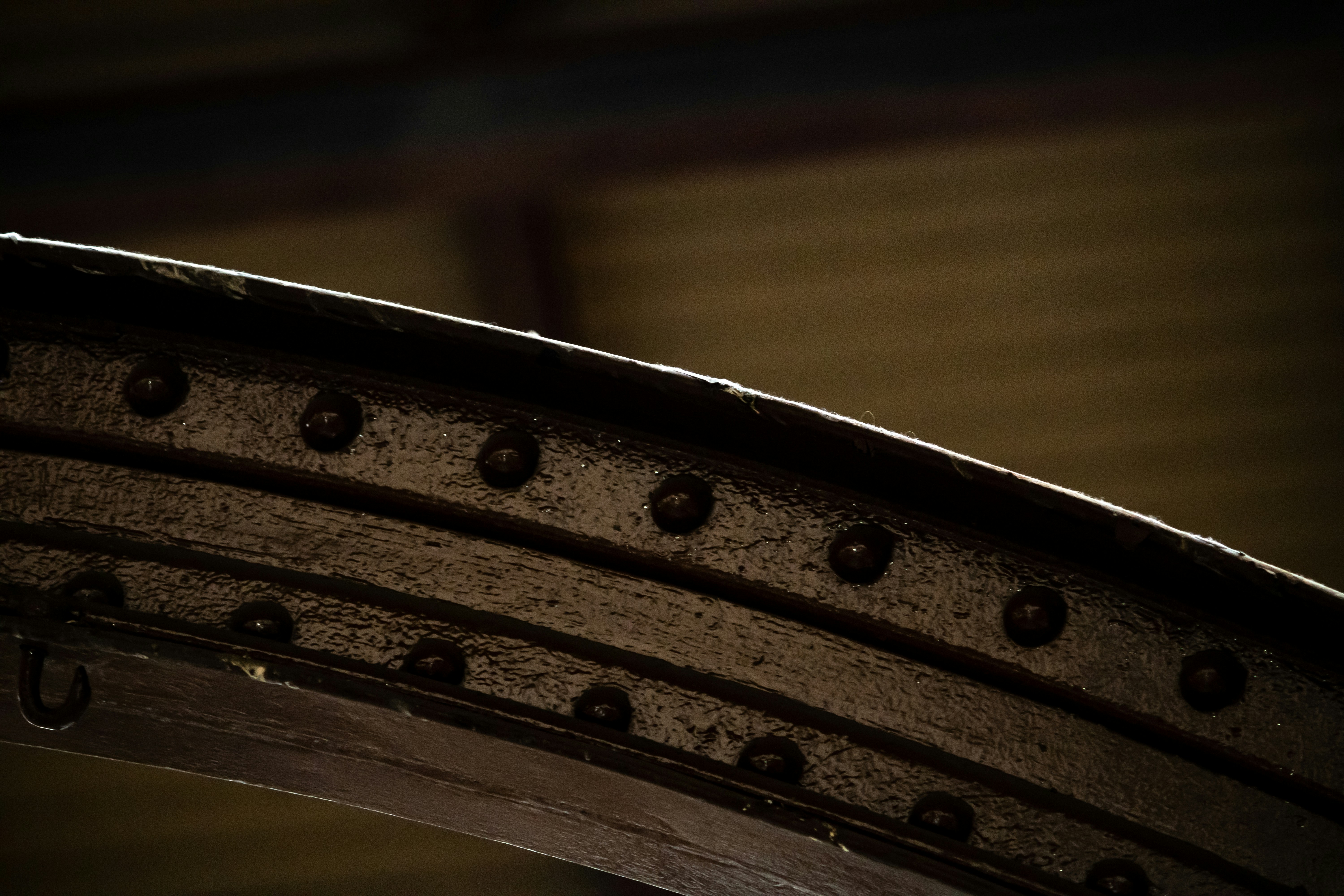 Riveted Arc in Dim Light: Close-Up of Weathered Steel