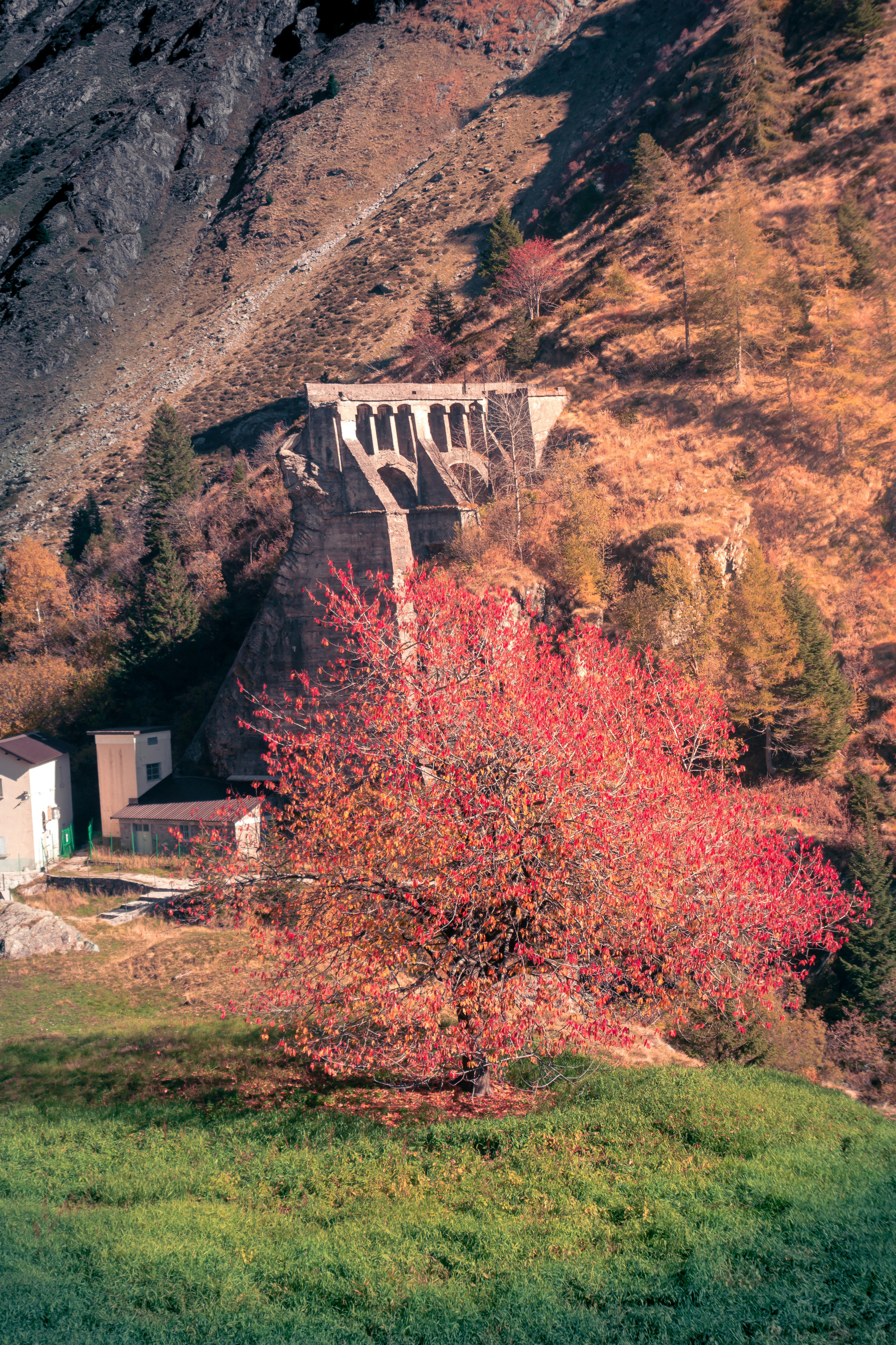 A large rock cliff with a building on it photo – Free Diga del gleno ...