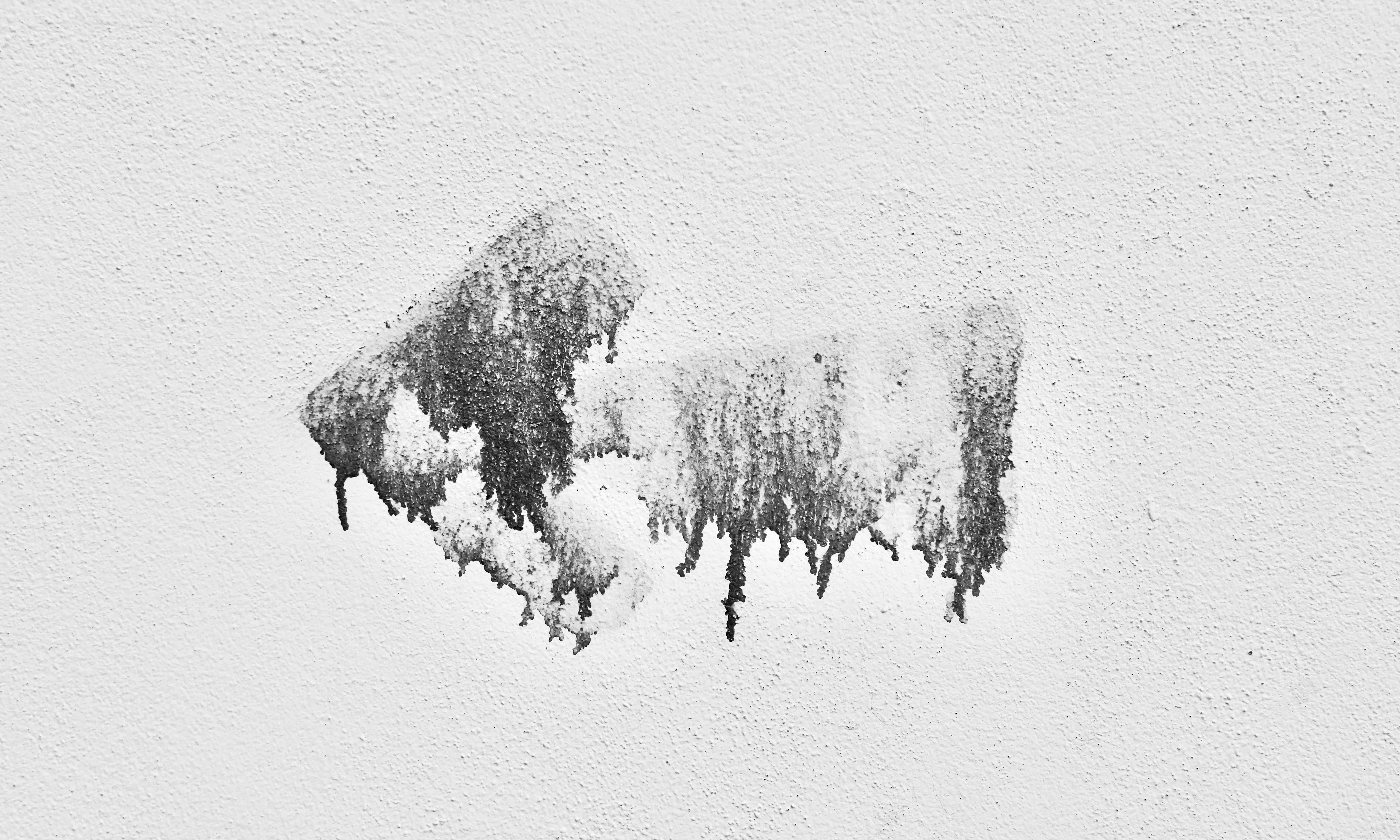 Abstract ink-streak texture on a light wall with drips and subtle grain; a minimalist wall art/texture sample.