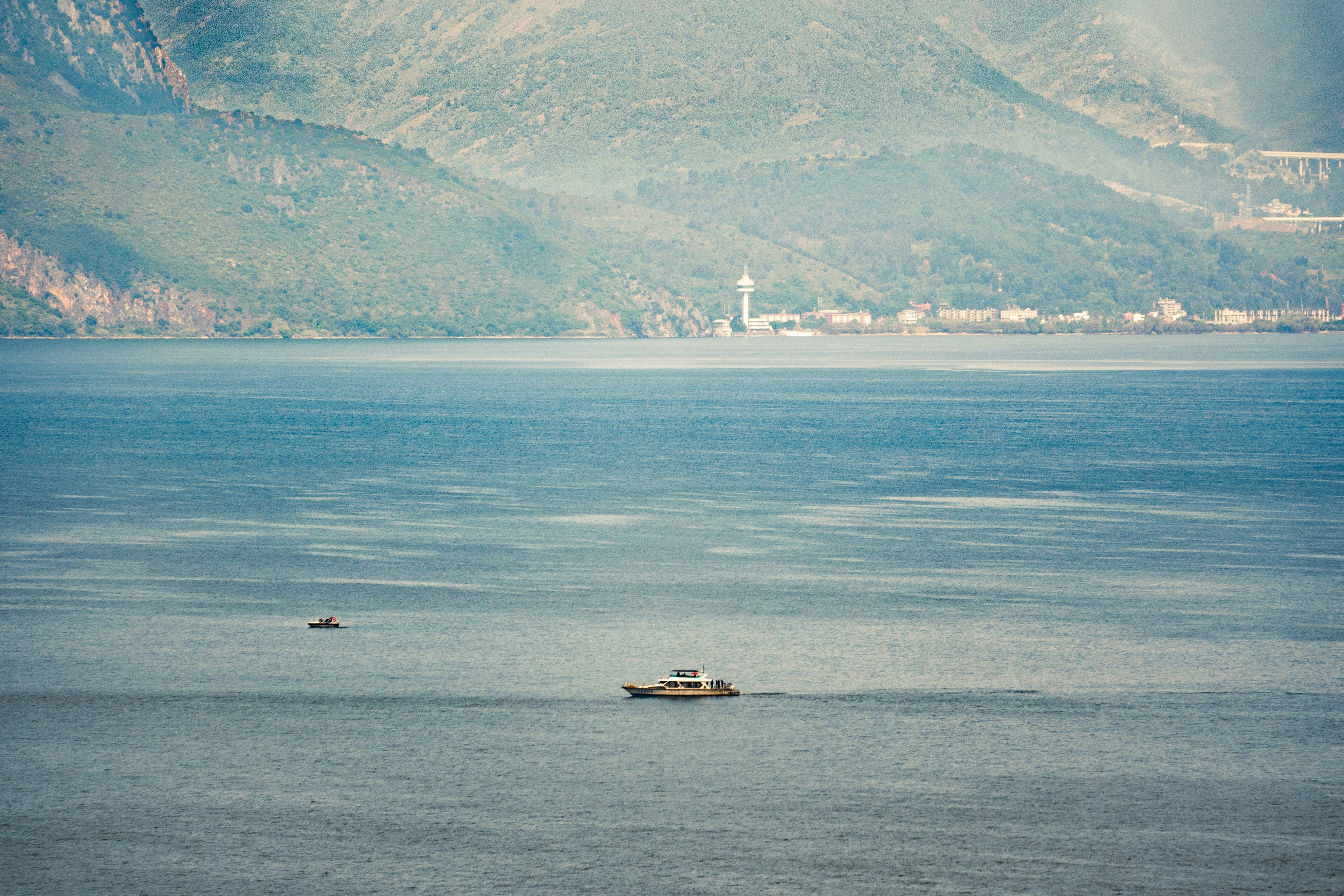 Calm Currents: Boats and Distant Lighthouse Framed by a Mountain Horizon