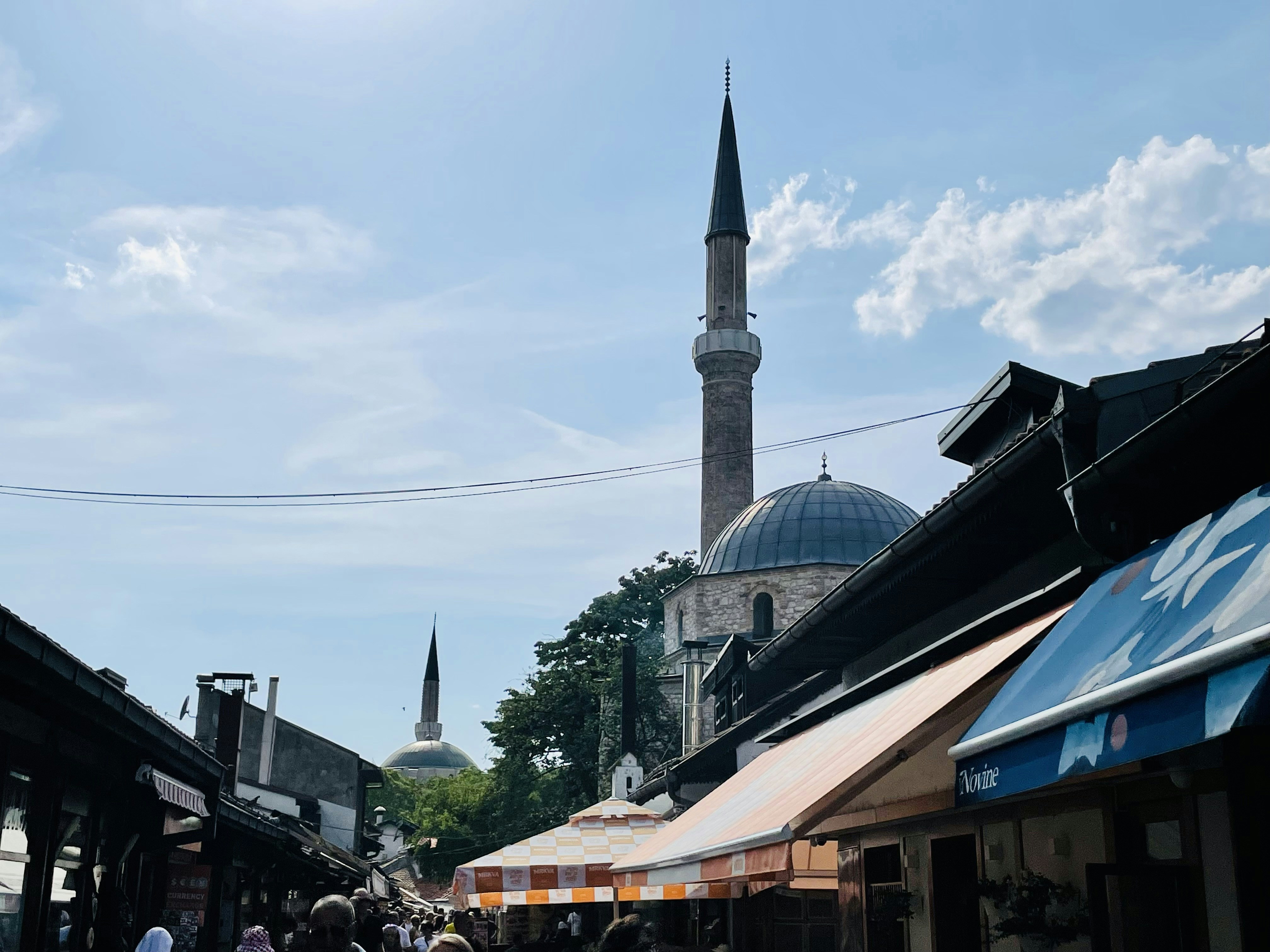 Bustling market street with tall minarets reaching into a clear blue sky.