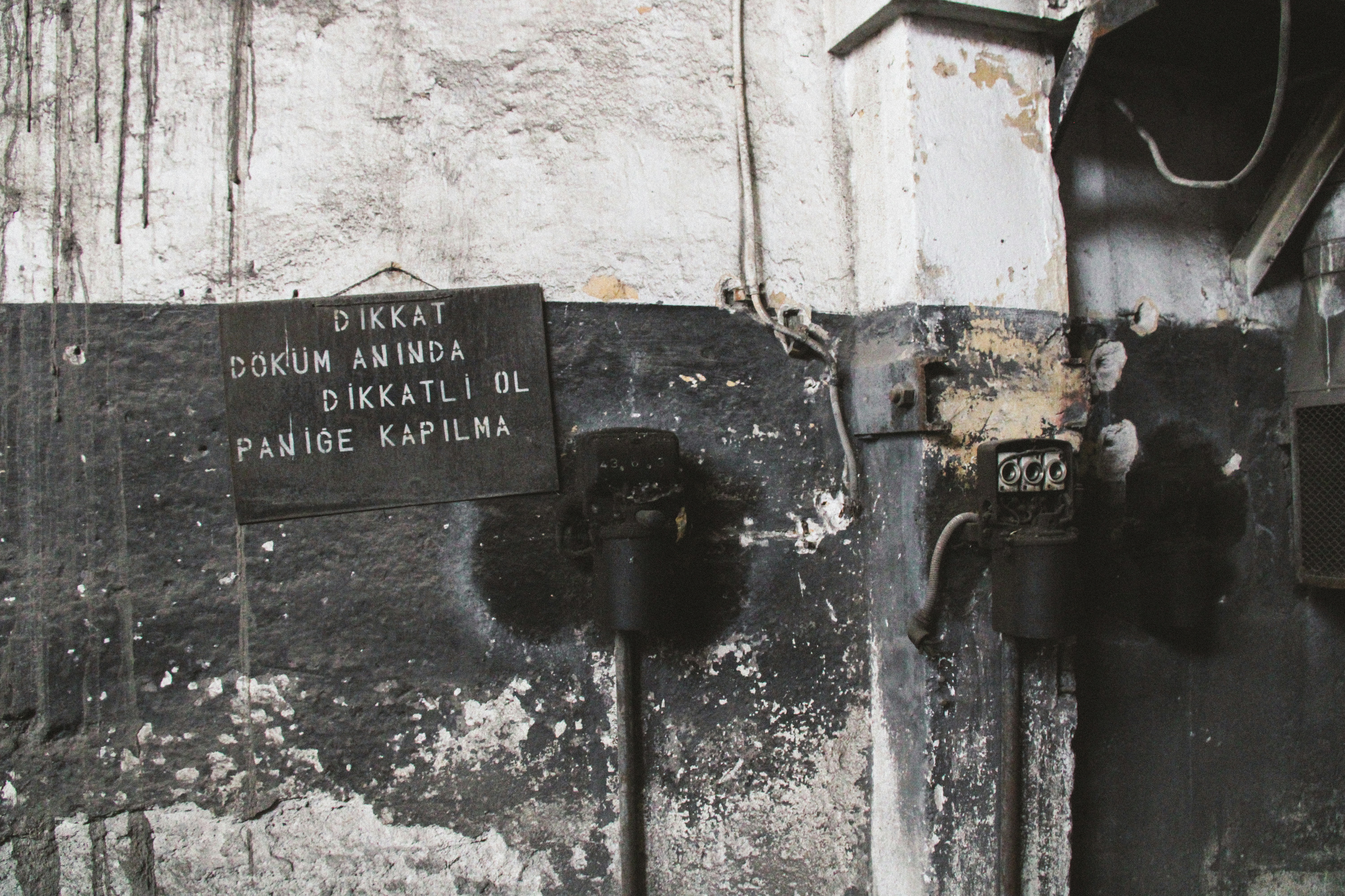 Caution Plaque on a Weathered Wall: Echoes of a Forgotten Utility