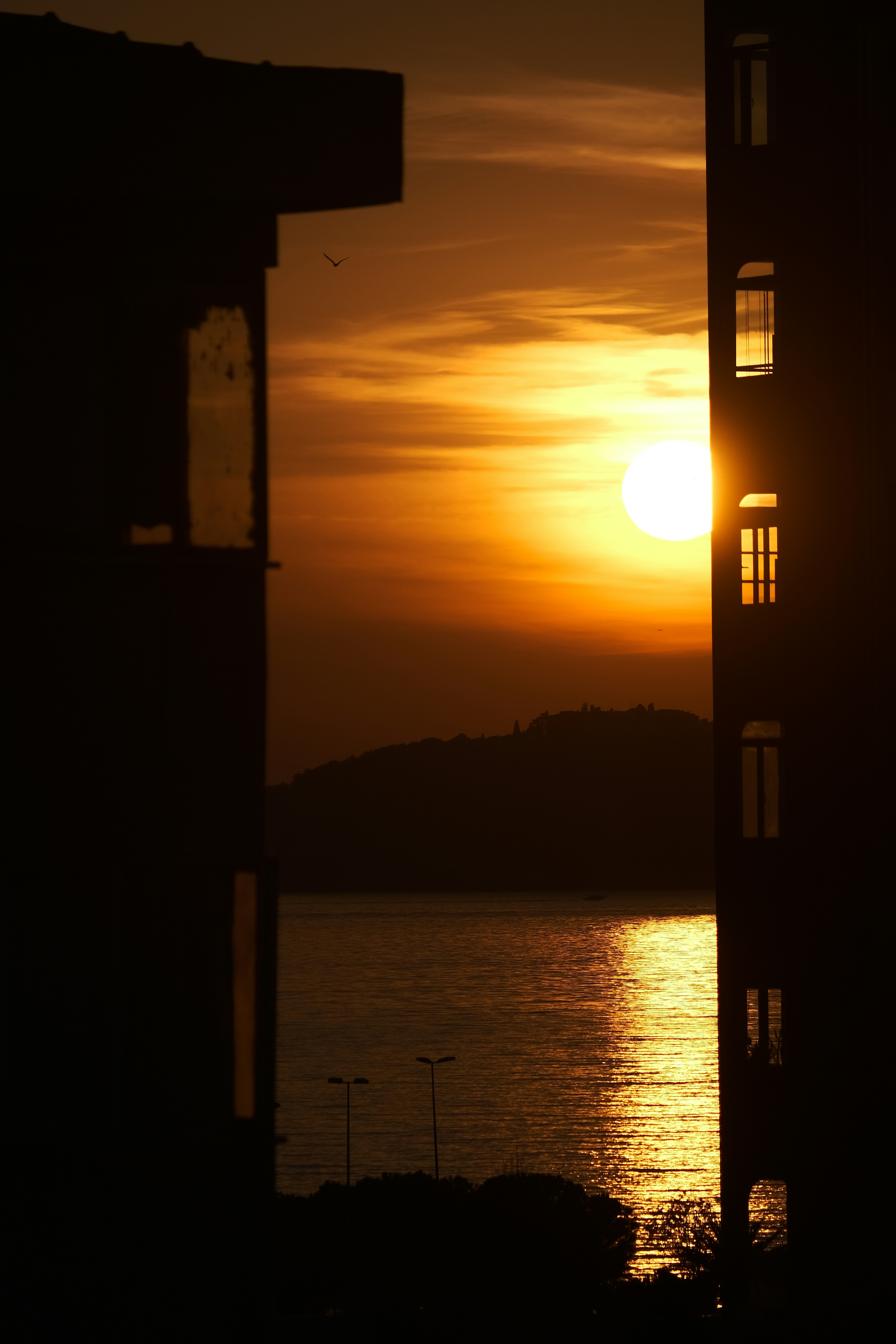 Sunlit Narrow Gap: Sunset Between Towers Over a Tranquil Bay