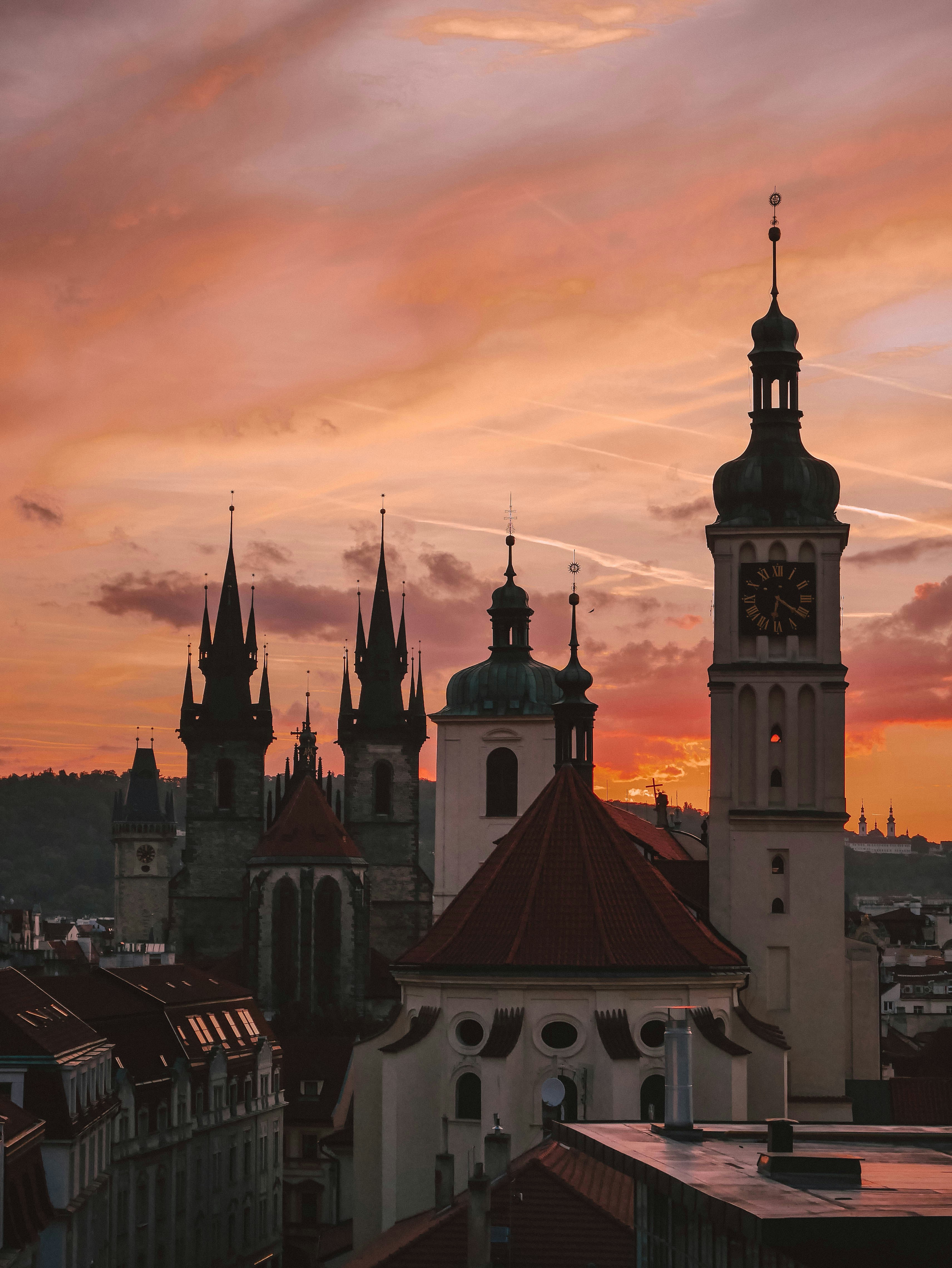 A sunset over the beautiful towers of Prague, showing the true magic of the city | a clock tower in a city