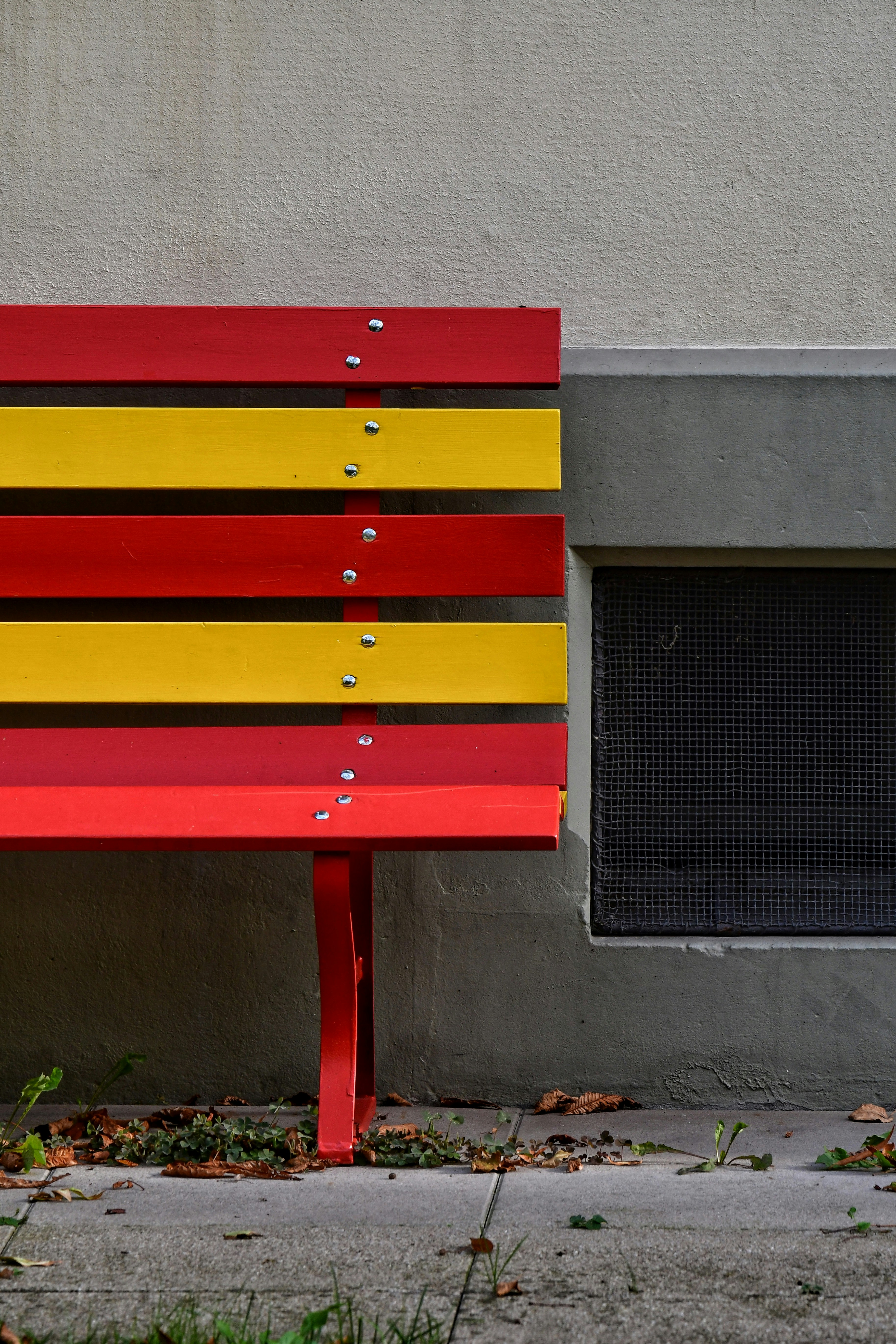 Urban Color Study: Red-Yellow Slat Bench by a Textured Wall