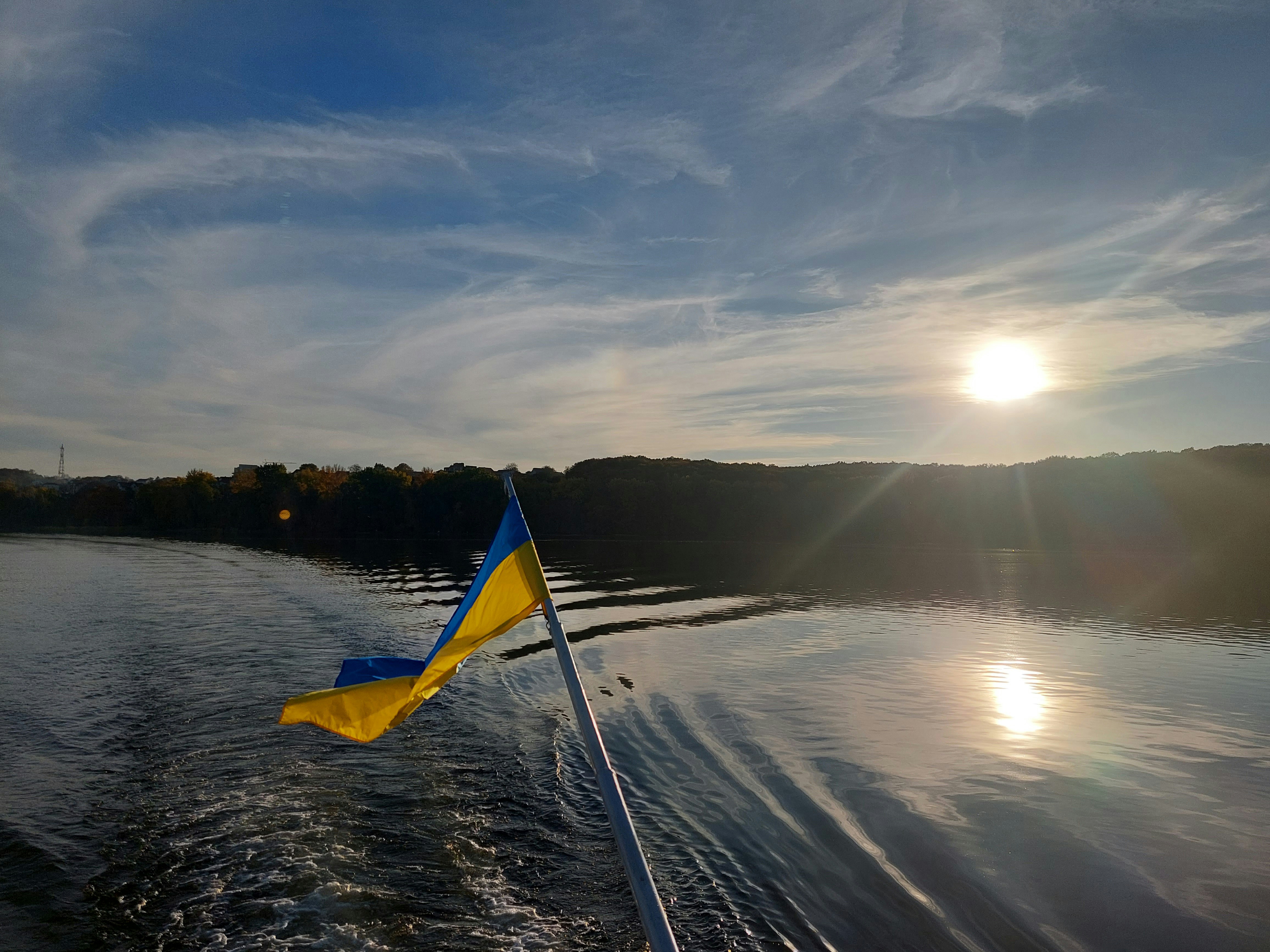 a flag on a boat in the water with the sun in the background