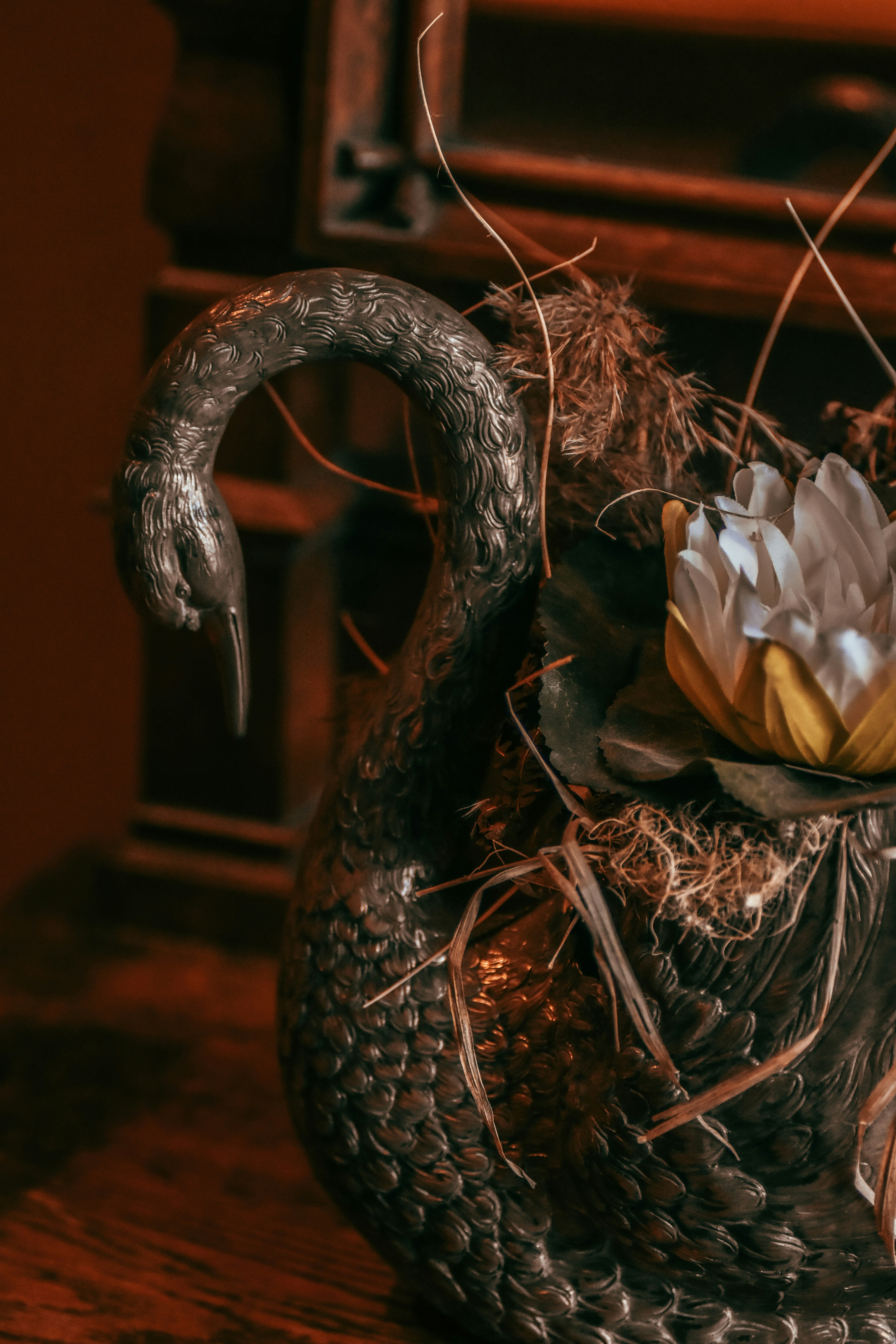 Ebony Flamingo Vessel Cradling a White Bloom in a Warm Wood Corner