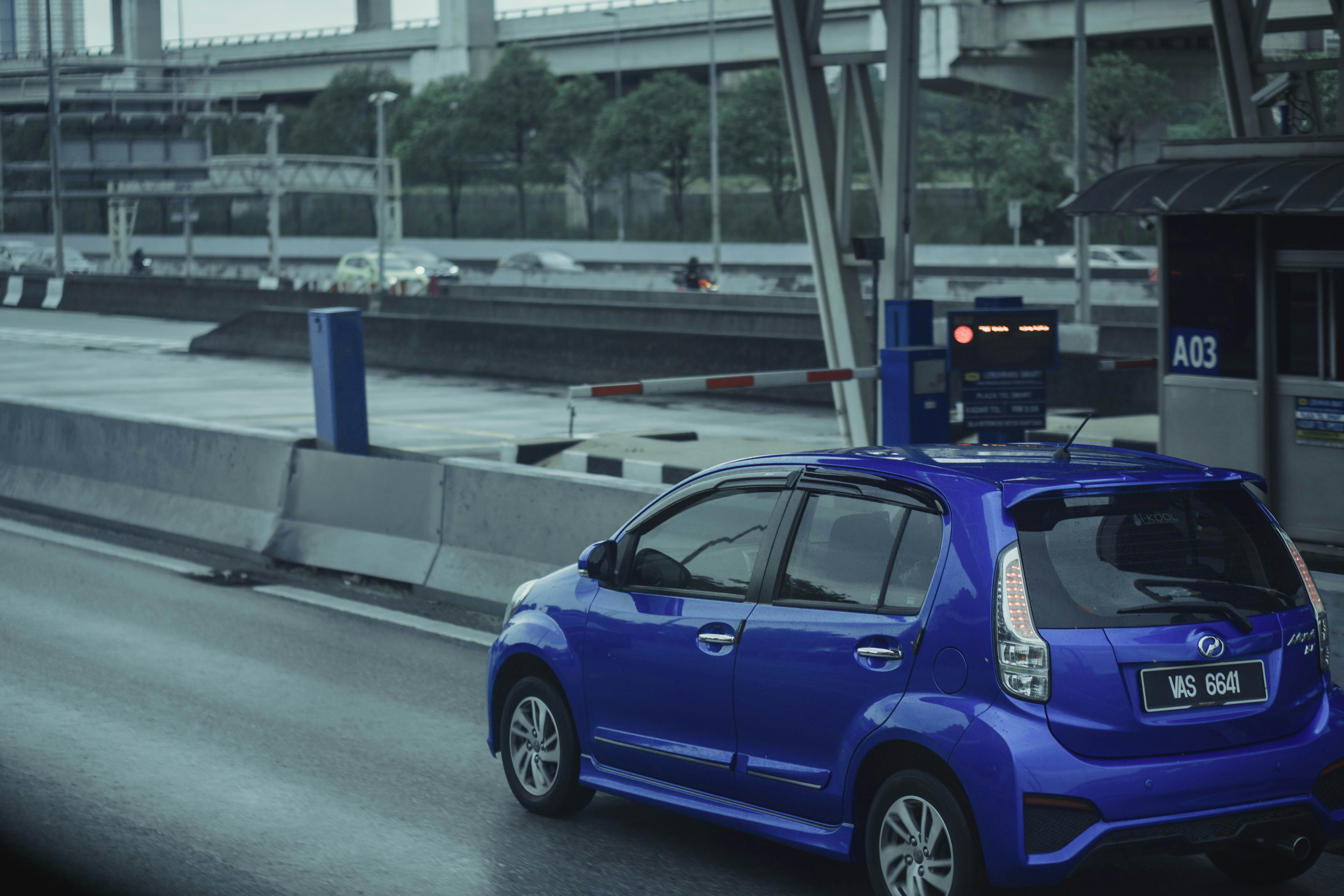 Blue Hatchback Navigates a City Highway Beneath Steel and Concrete