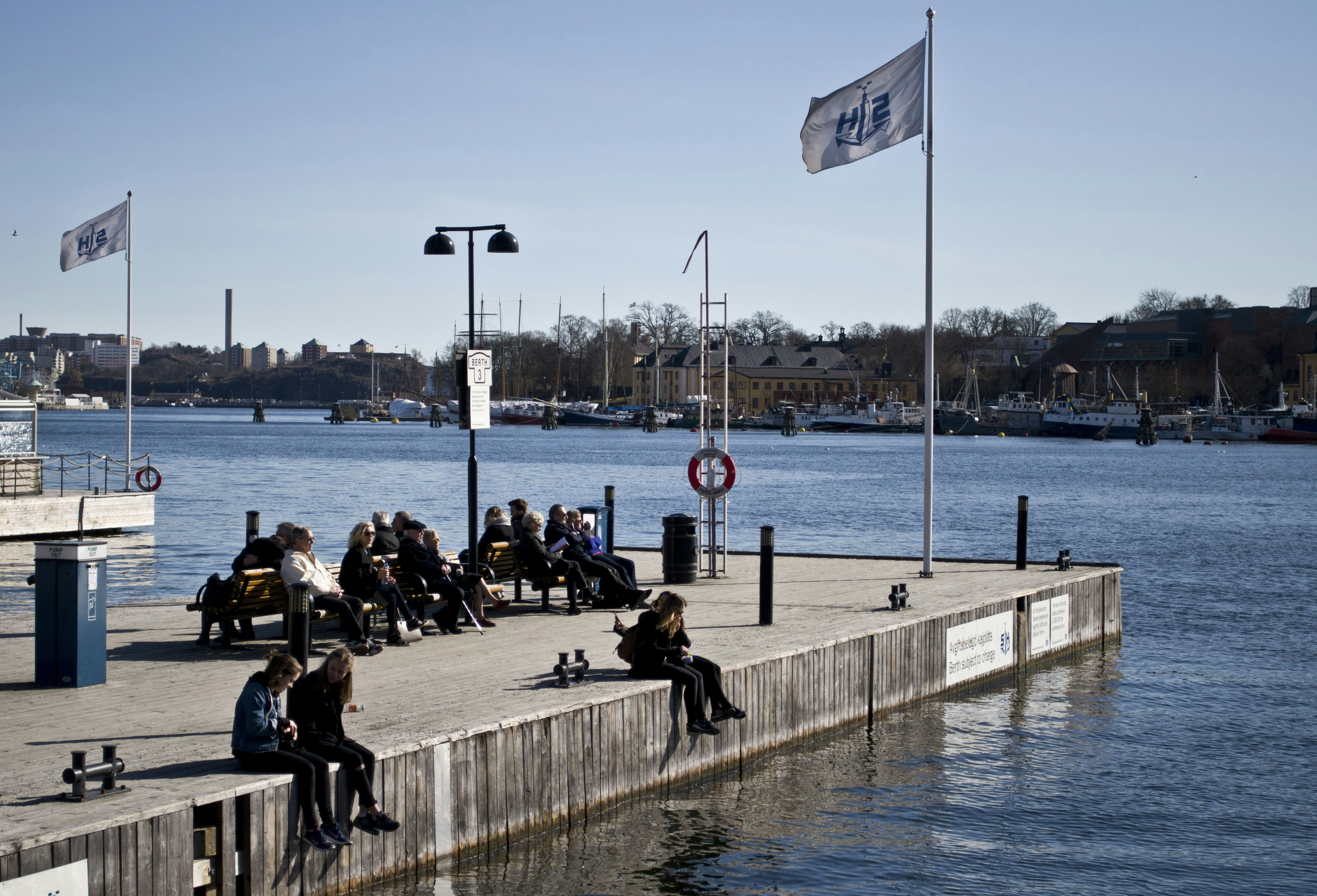 A group of people sitting on a dock by a body of water photo – Free ...