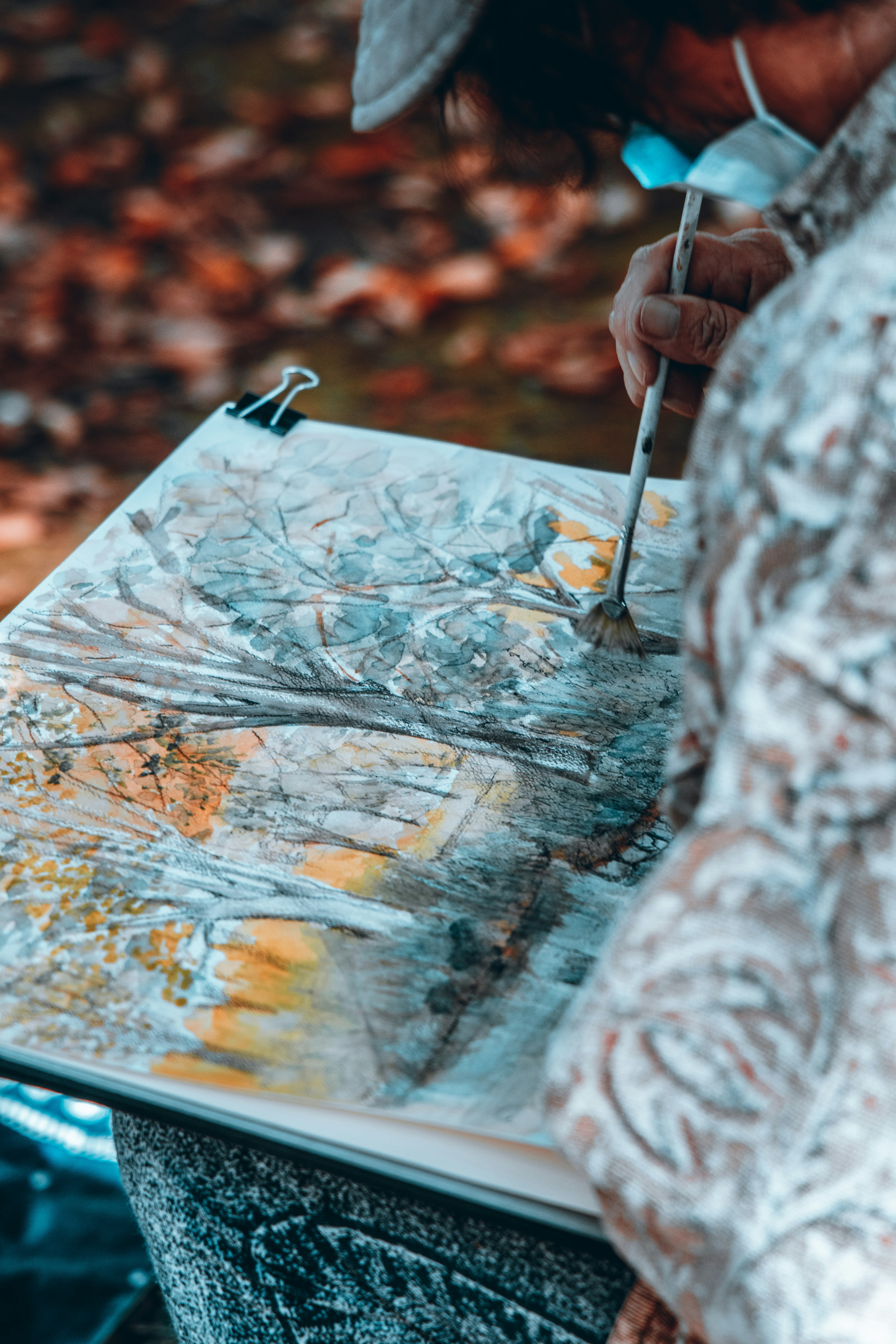 Masked Painter in an Open-Air Studio: Brushstrokes Amid Autumn Light
