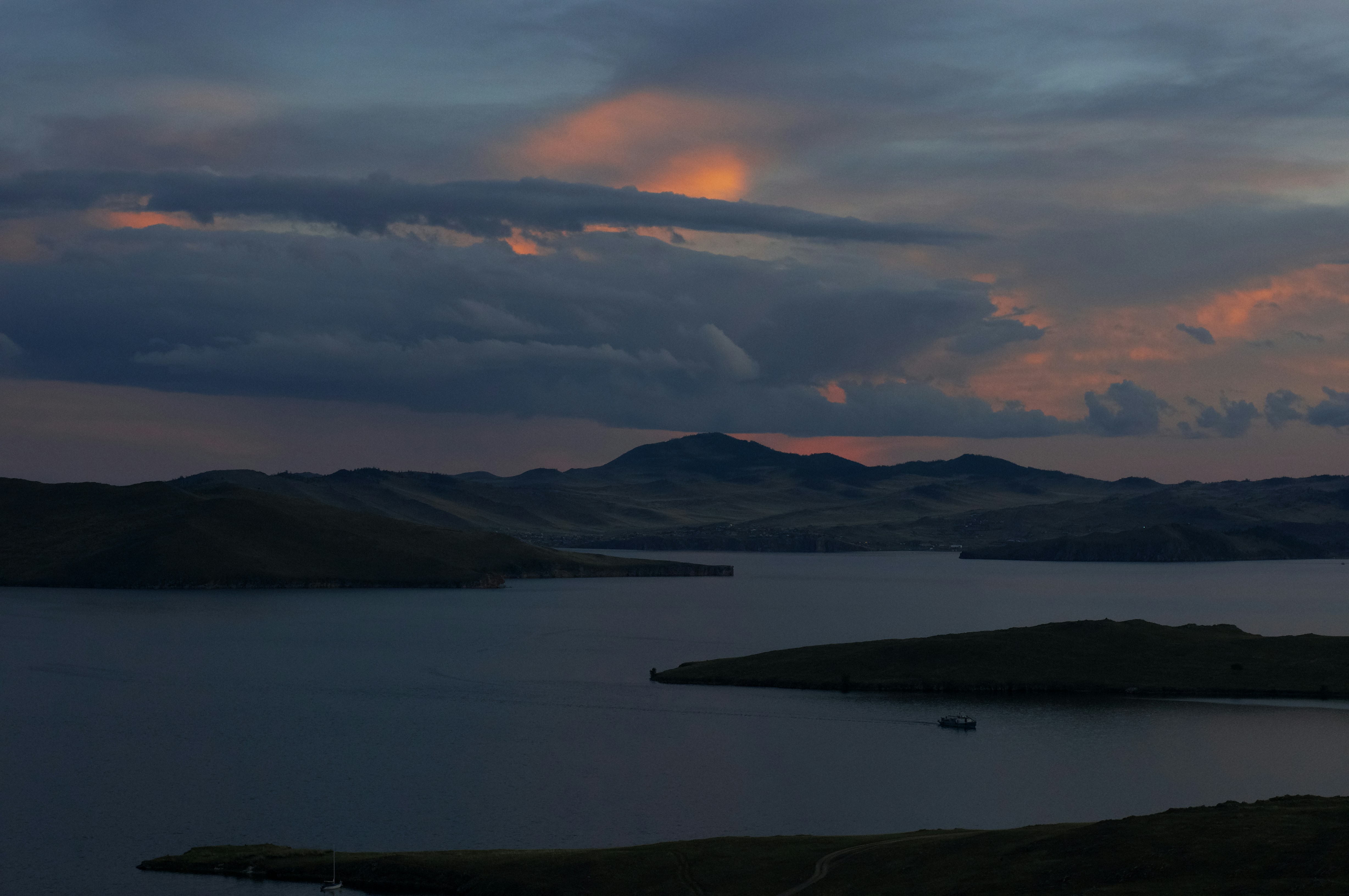 Dramatic clouds tinged with sunset hues over the tranquil waters of Lake Baikal.