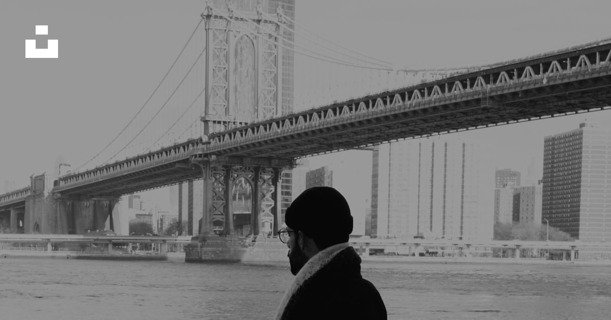 Foto Un Hombre Parado En Una Orilla Rocosa Mirando Un Puente Imagen