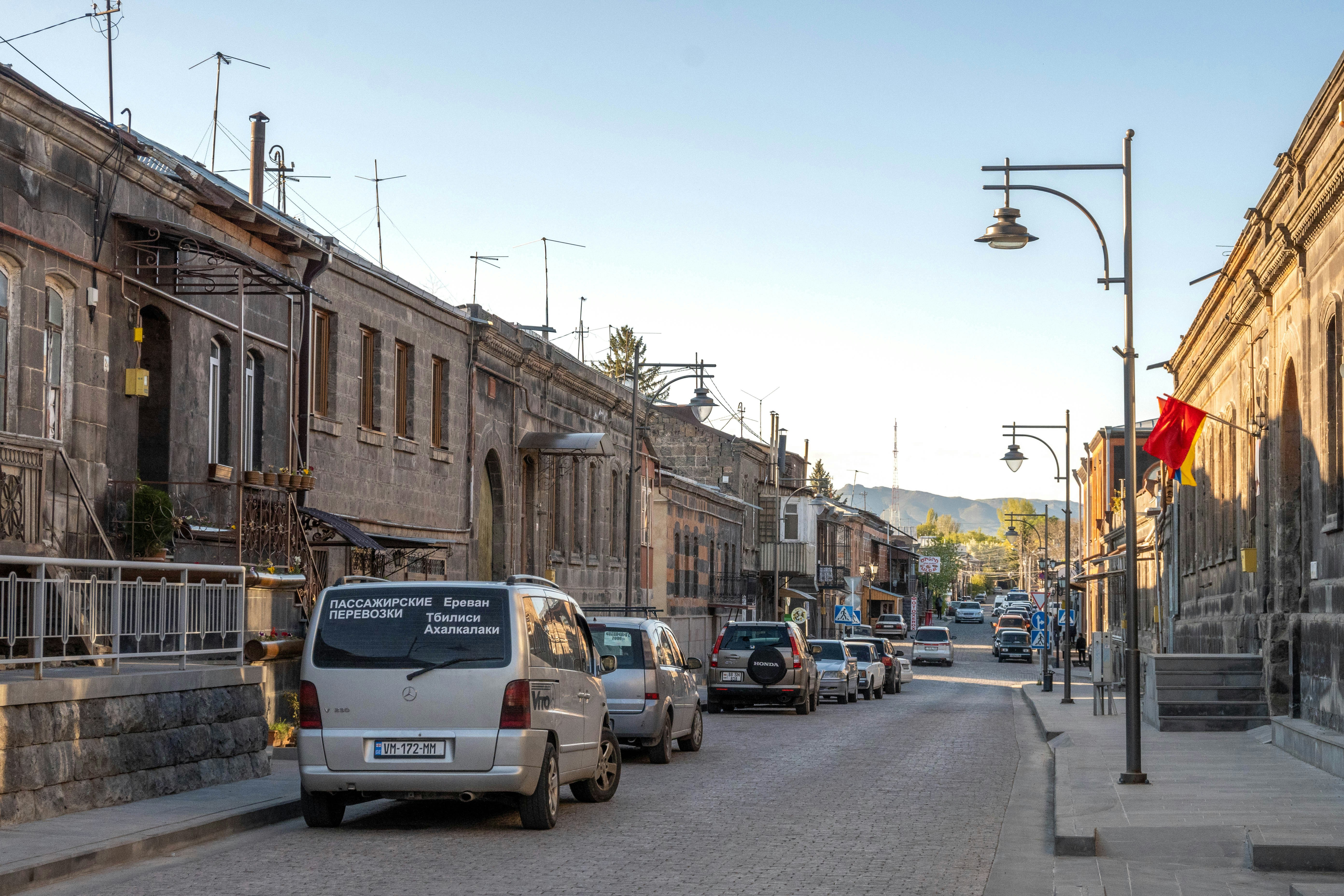 Quiet street in Gyumri lined with vintage stone buildings under a clear sky.