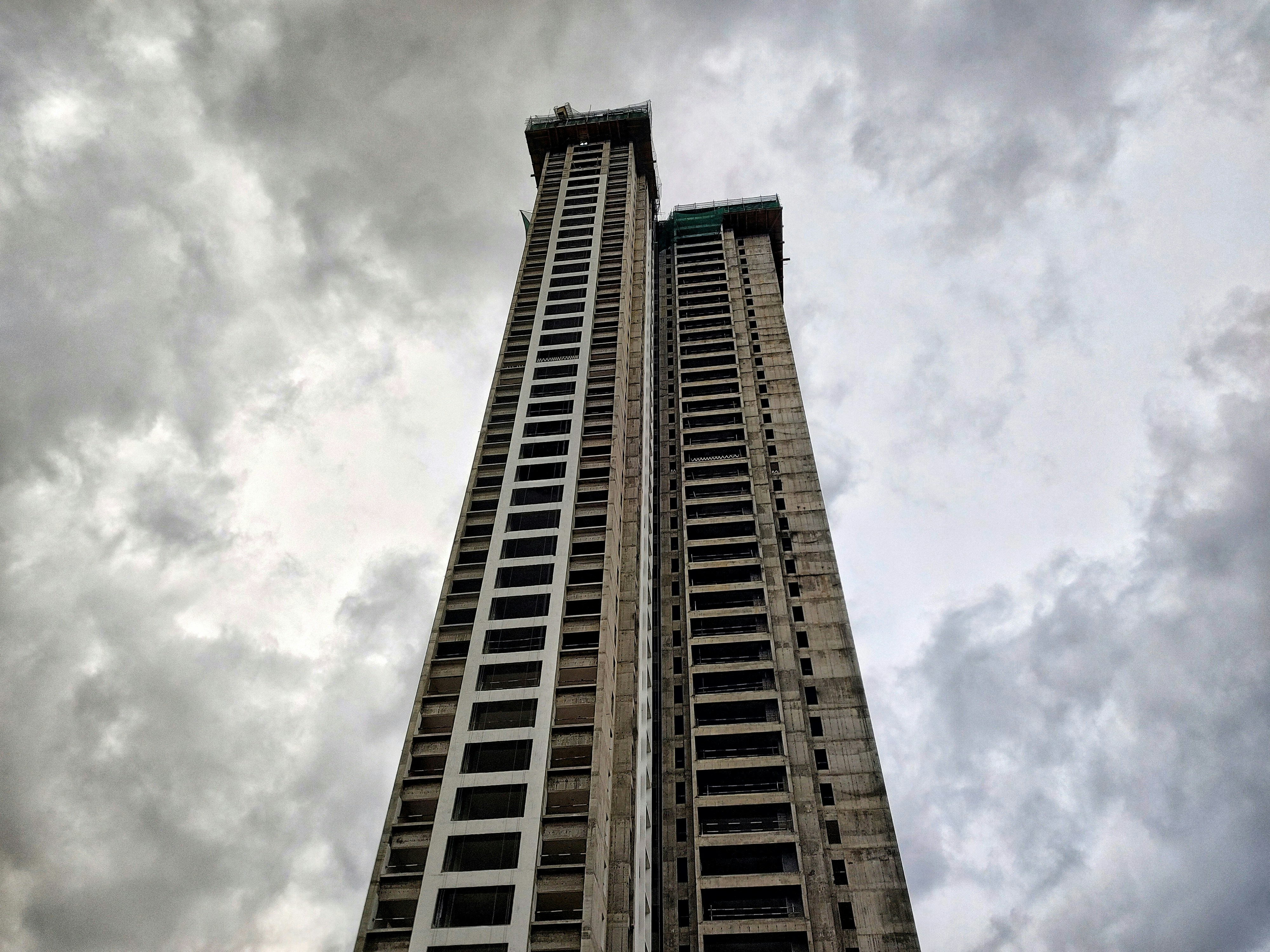 Two towering skyscrapers rise against a moody sky, showcasing the raw beauty of urban construction. The buildings appear unfinished, hinting at ongoing development.