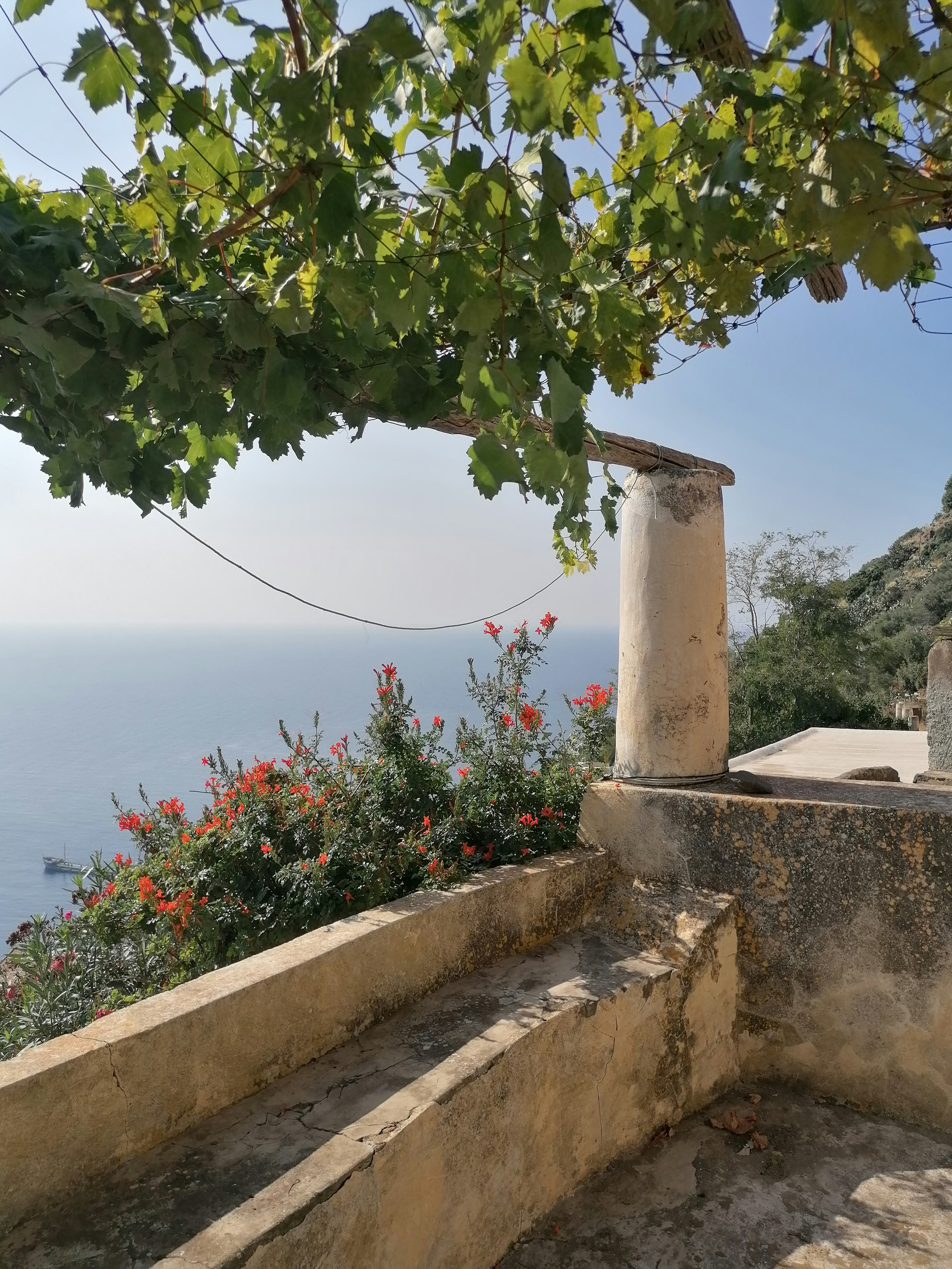 Un mur de pierre avec un pilier de pierre et un arbre avec des fleurs ...