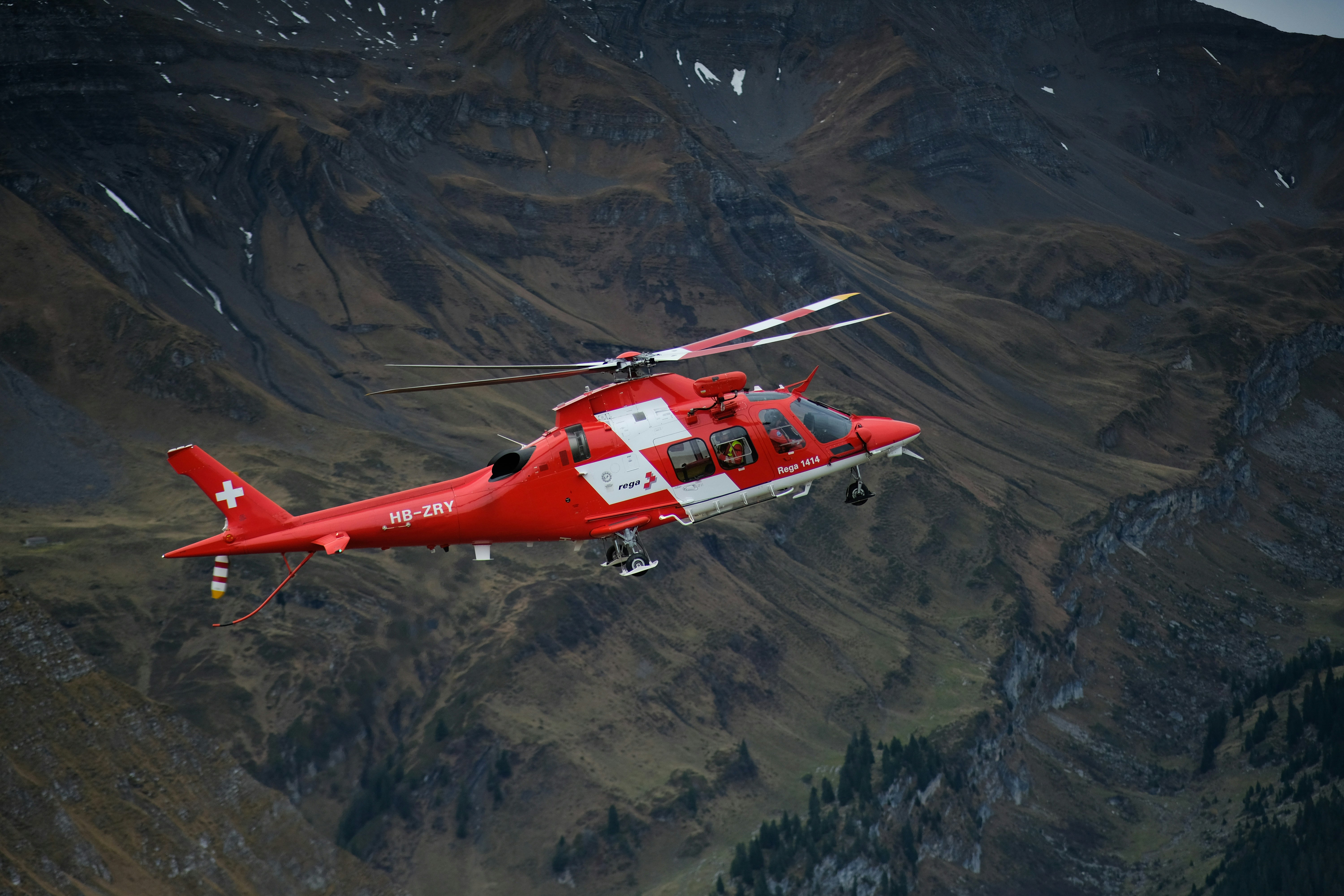 A red and white helicopter flying over a mountain photo – Free ...