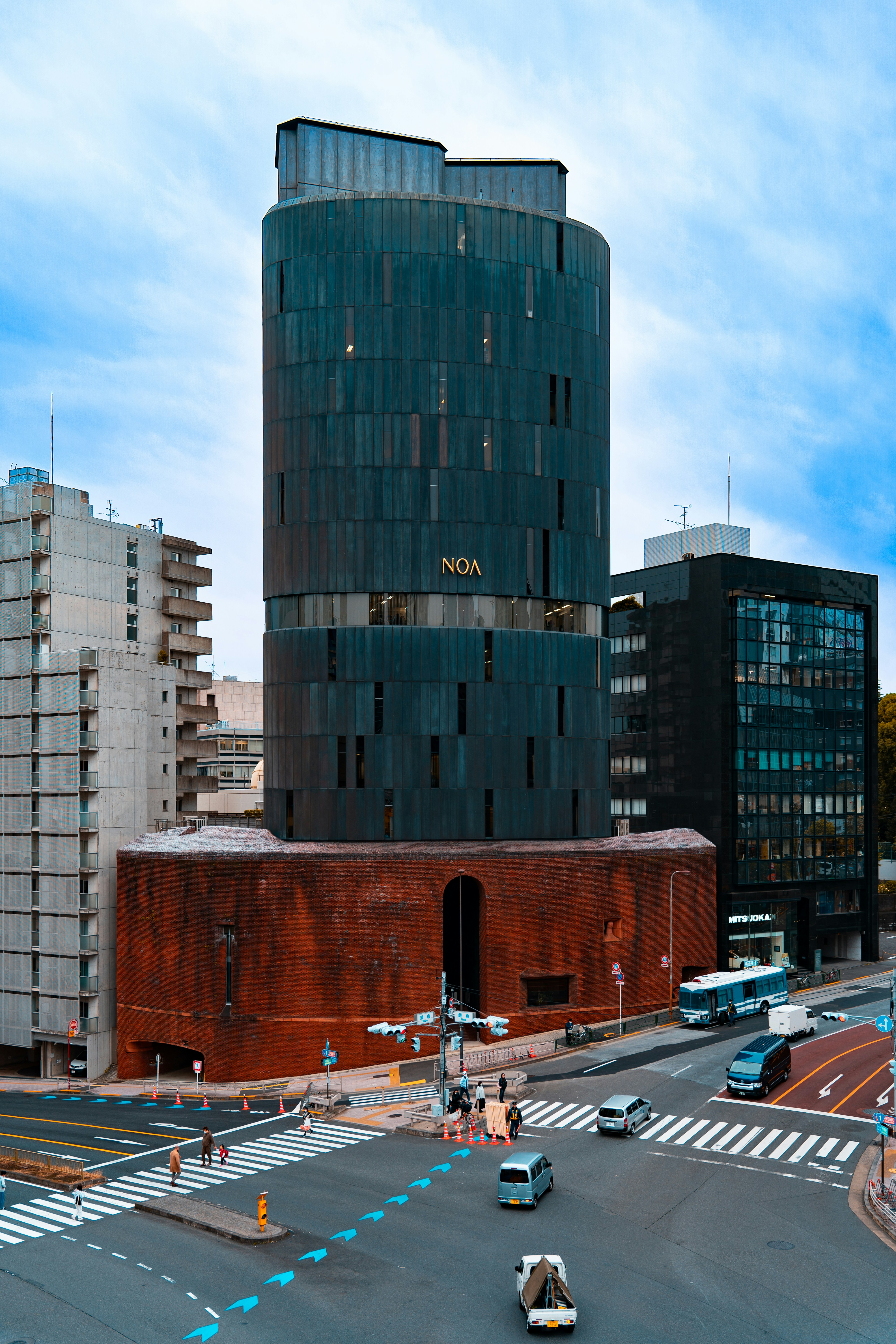 NoA Tower: Teal Cylinder Rising Above Brick and Glass